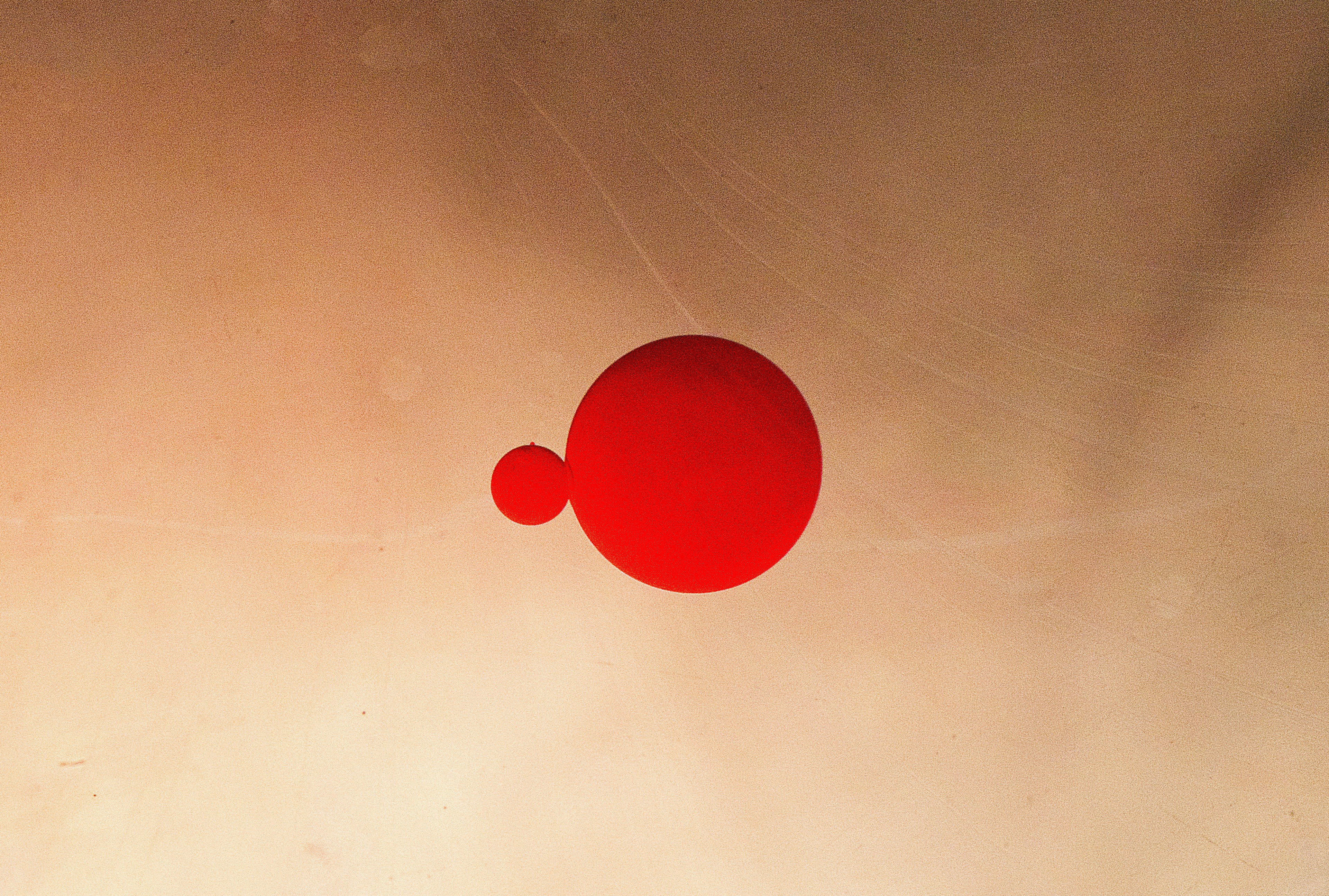 Red Sphere with Subtle Halo in Soft Peach Backdrop