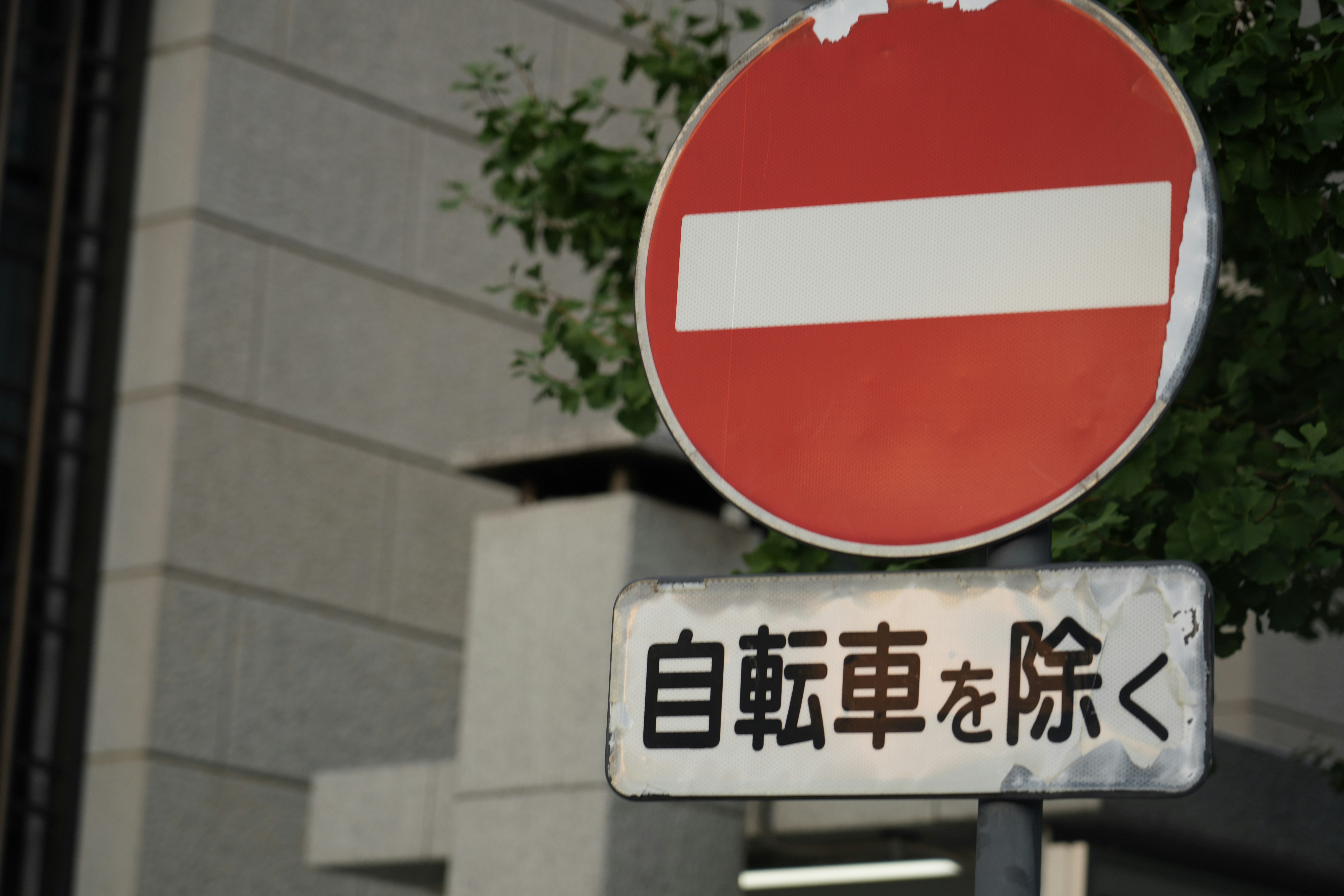 Red Stop Sign with Japanese Safety Sign Against Urban Concrete