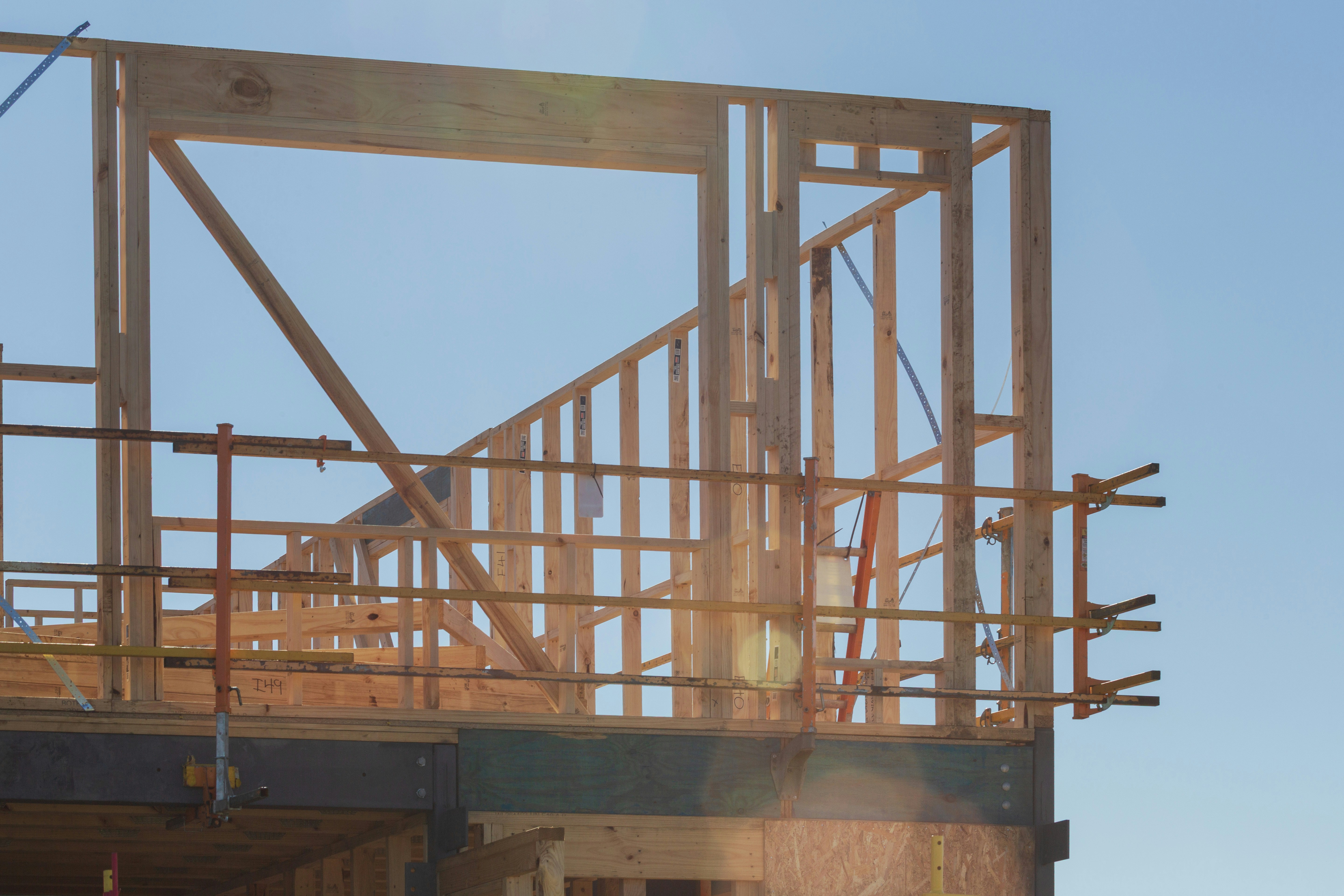 Framework in the Sun: Wooden Skeleton Rising Against a Clear Sky