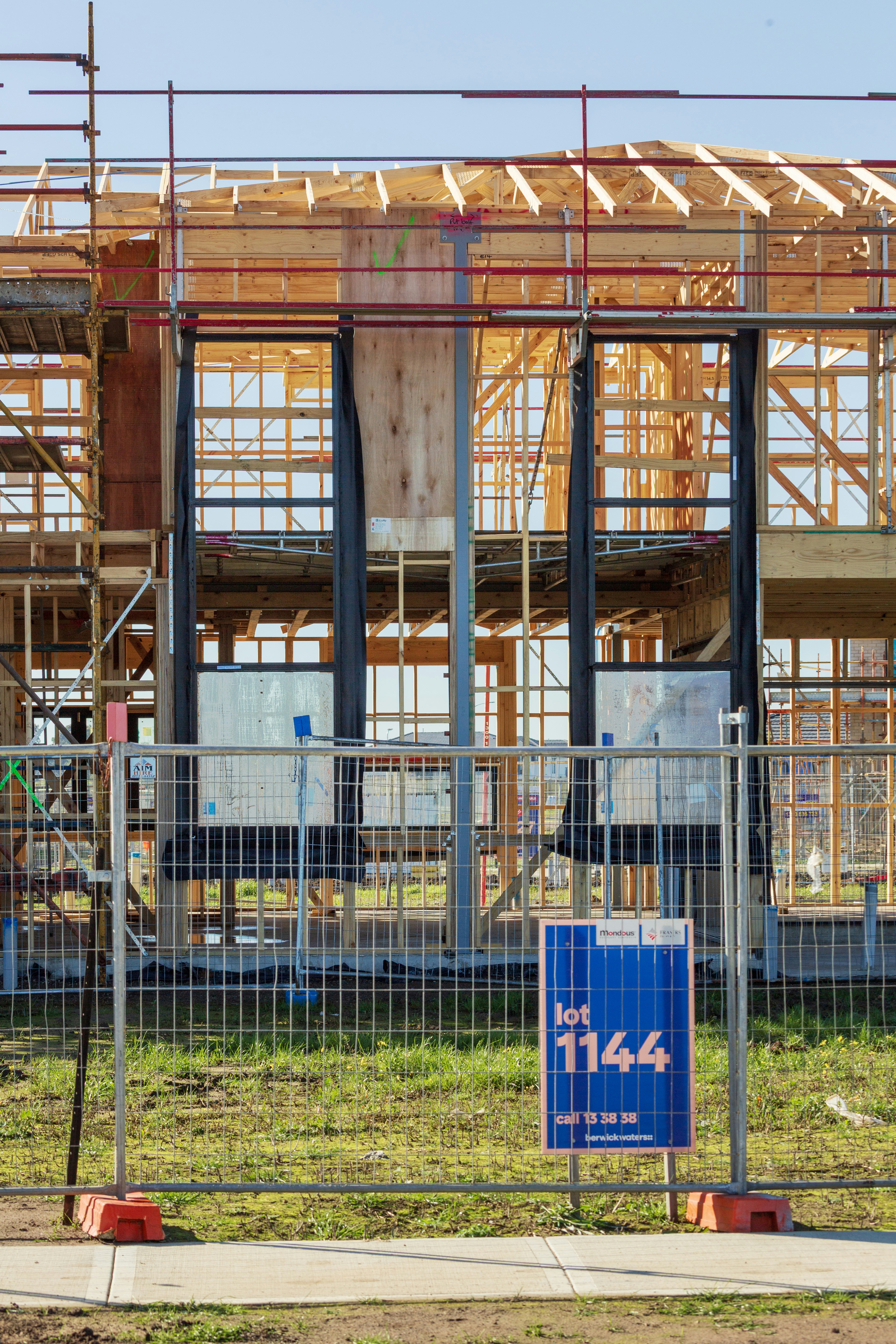Skeleton of a Modern Building: Timber Frame behind a Security Fence