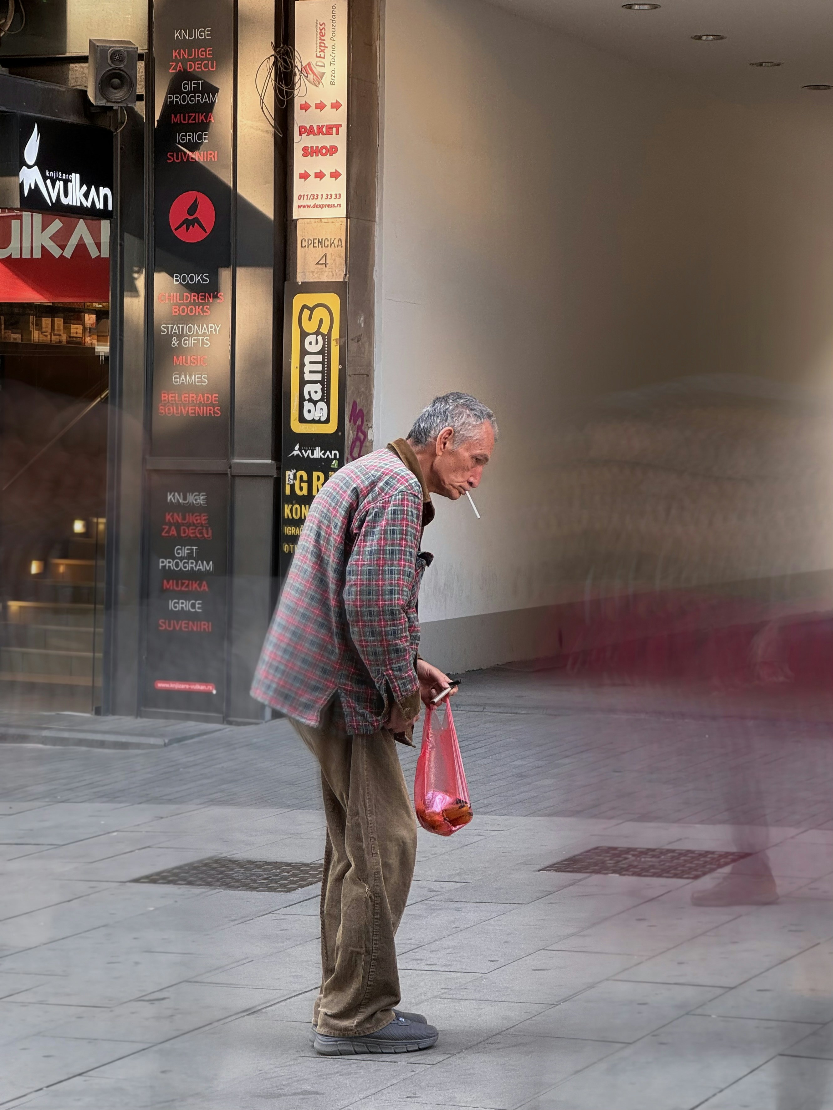 Senior Street Vendor in a Quiet Moment Outside the Shopfronts