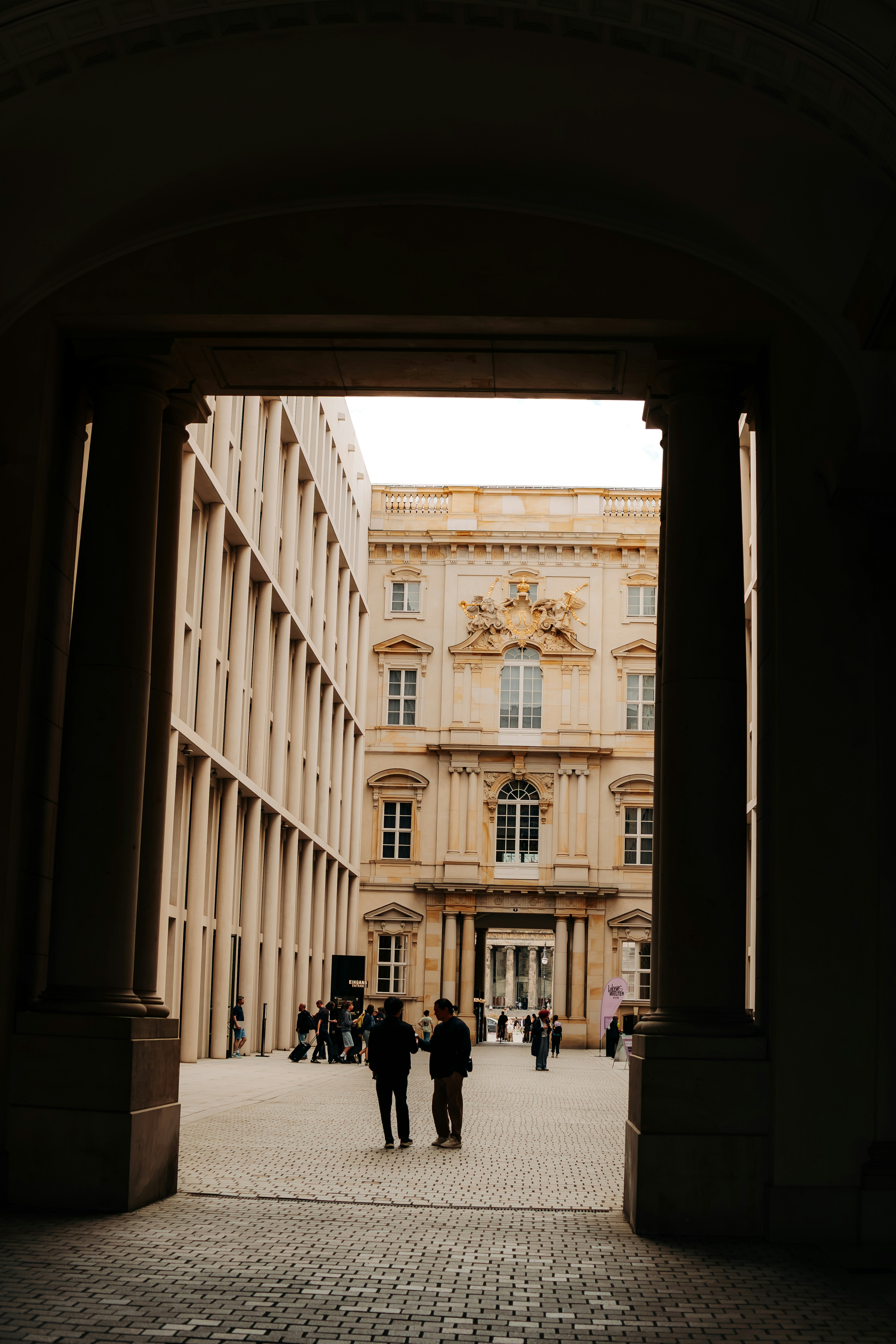 Lighted Archway: People in a European Courtyard Framed by Columns