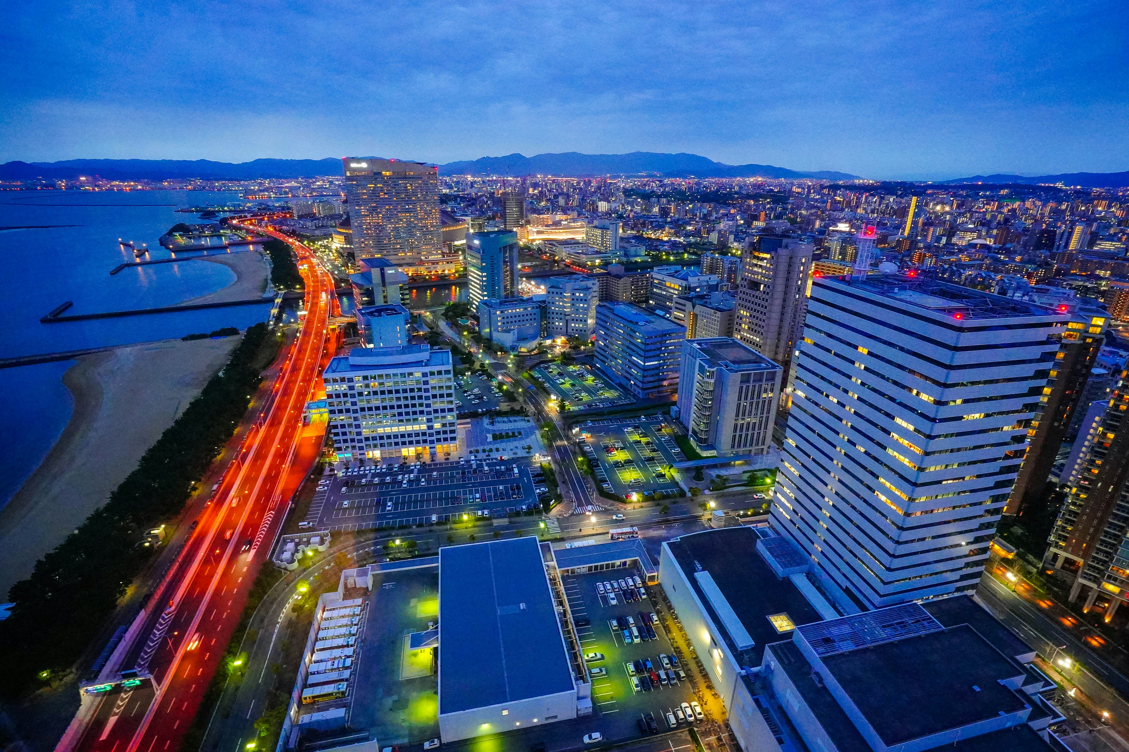 Aerial Pulse: Night Corridor of Light Over a Coastal City