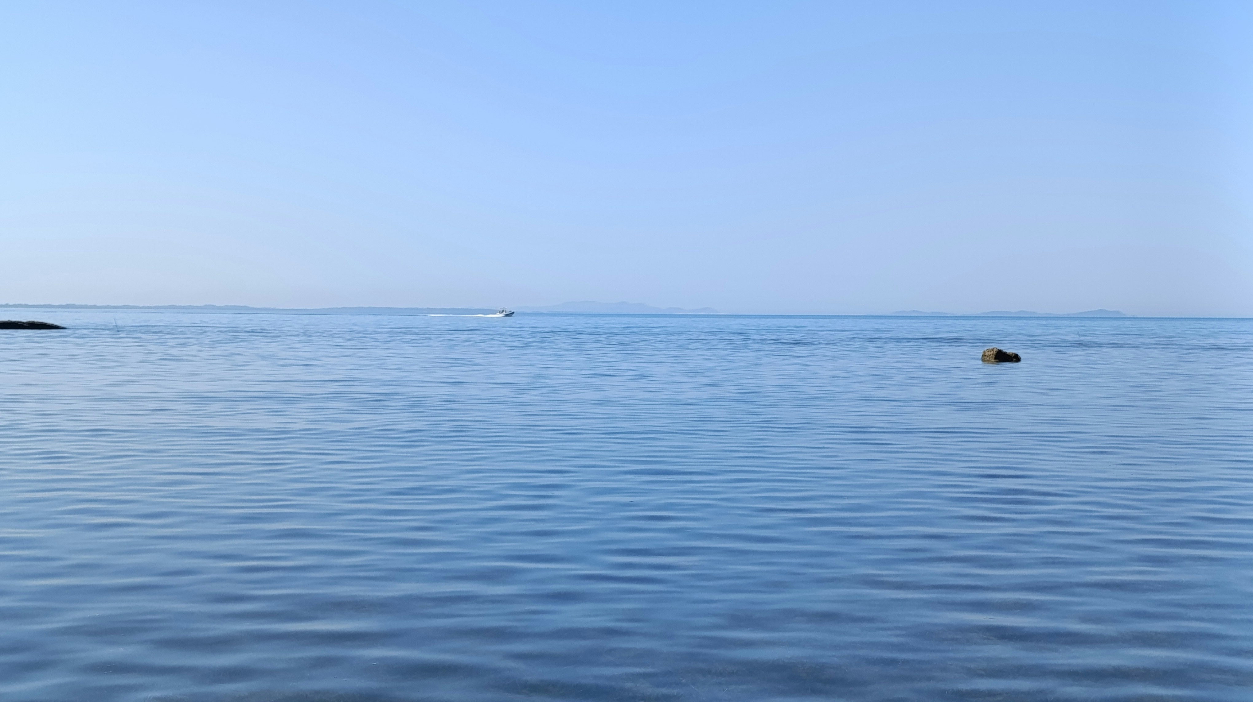 A tranquil seascape with distant horizon and gentle ripples on the water; the scene emphasizes open water and sky with minimal foreground features.
