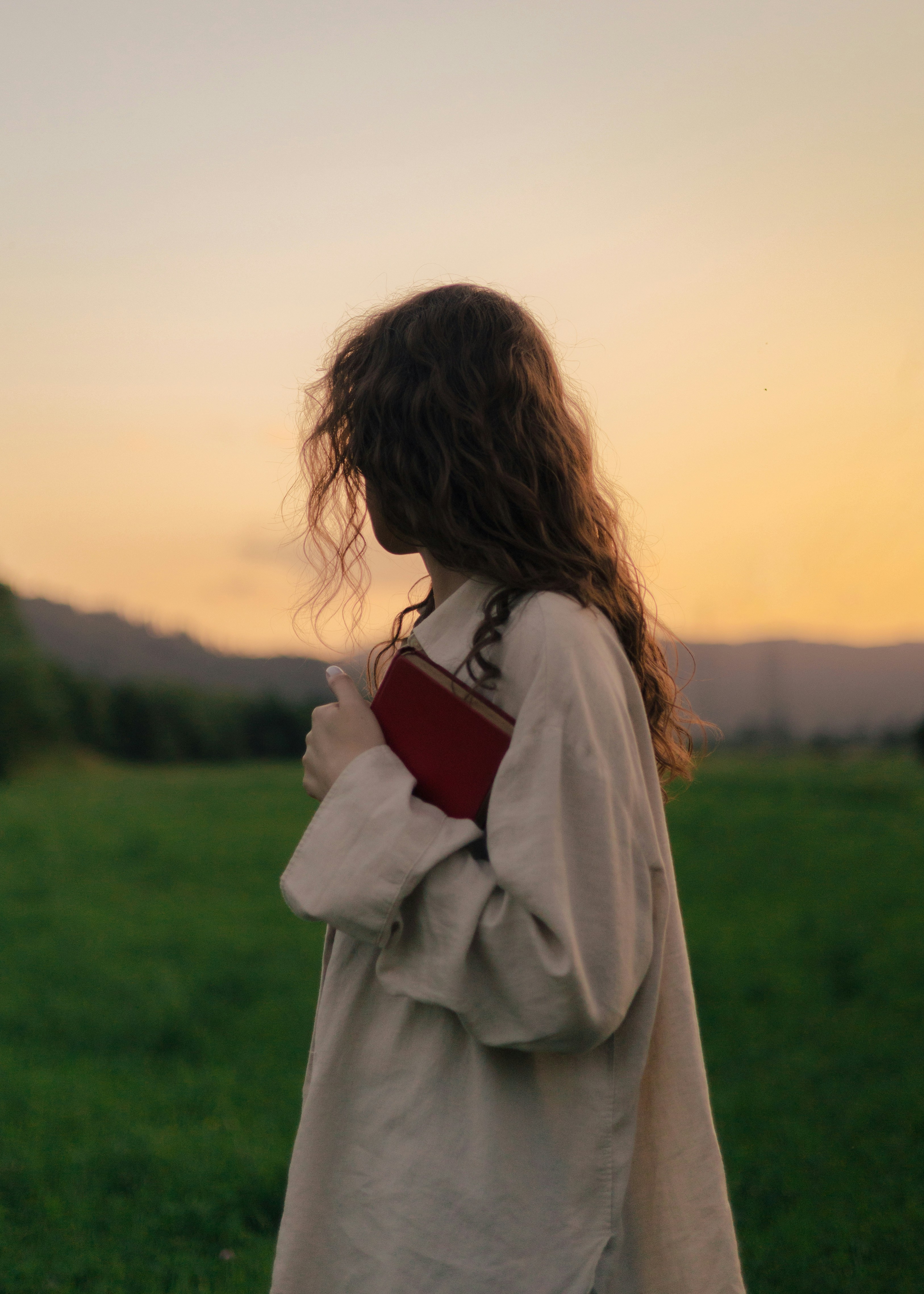Whispered Sunset: A Woman with a Red Notebook in a Quiet Field
