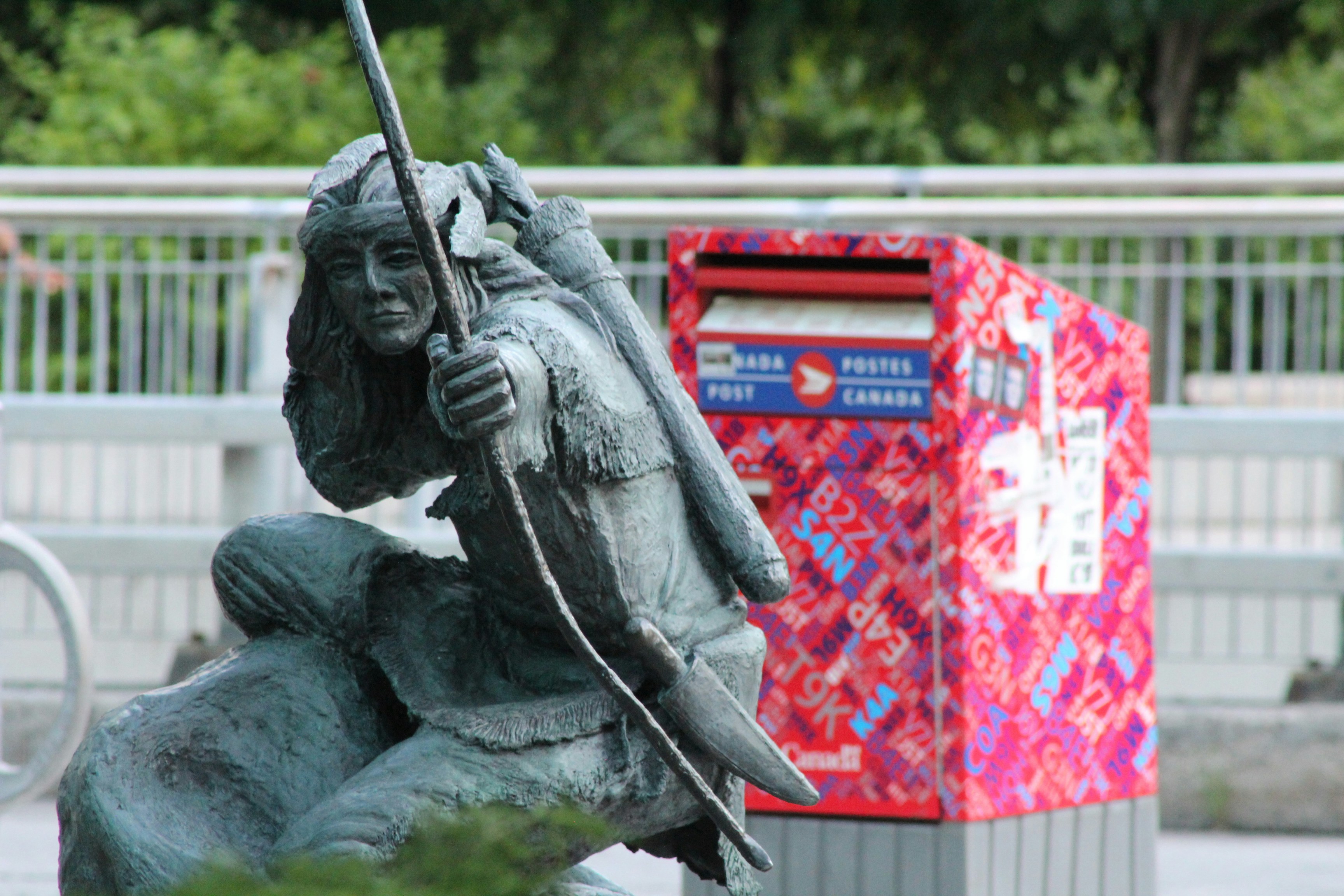 Archer of the Dockside: A Warrior Statue Beside a Colorful Mail Box