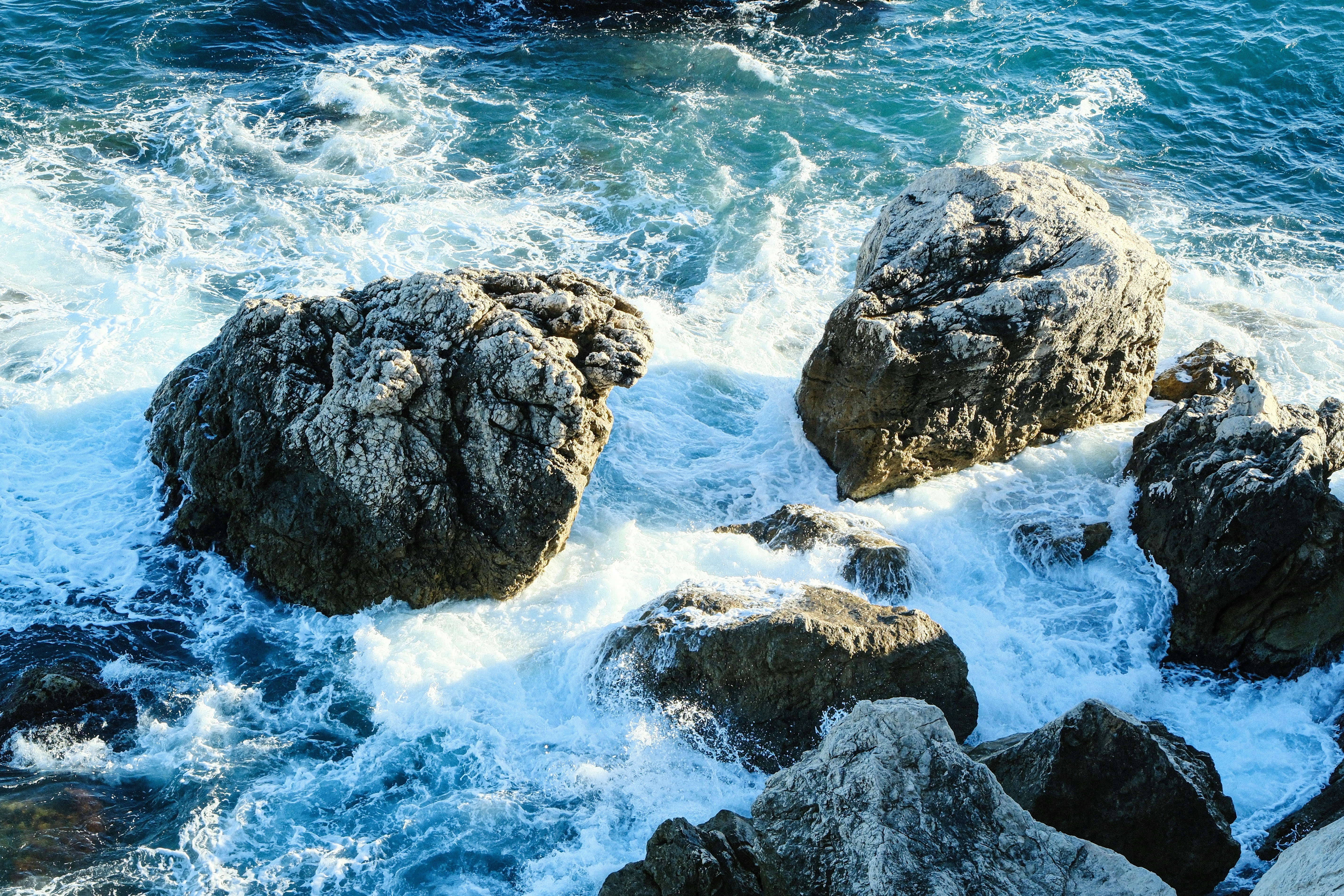 Rugged shoreline: sunlit rocks amid surf and foam