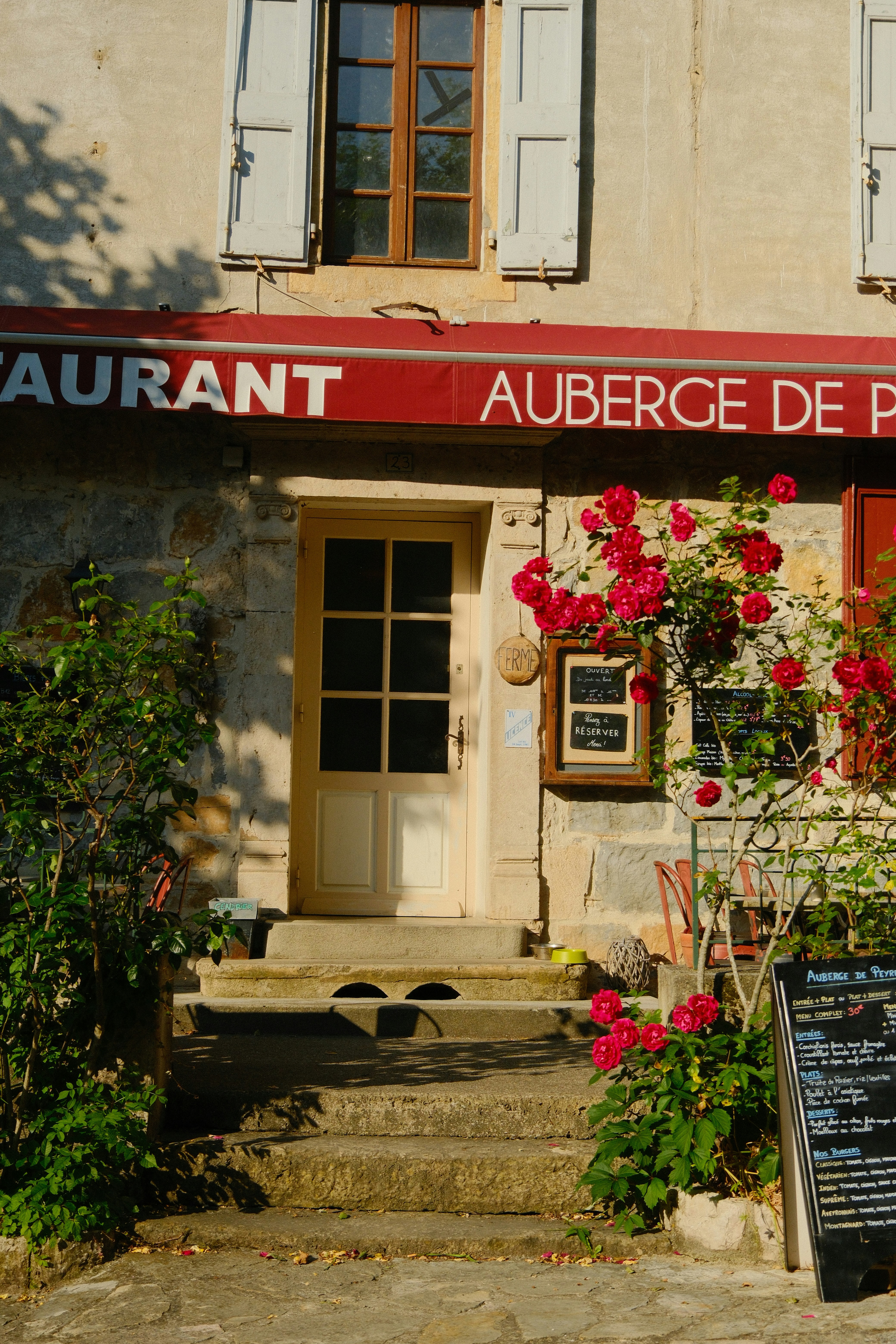 Rose-fronted Bistro: A Sunlit Doorway in a French Courtyard