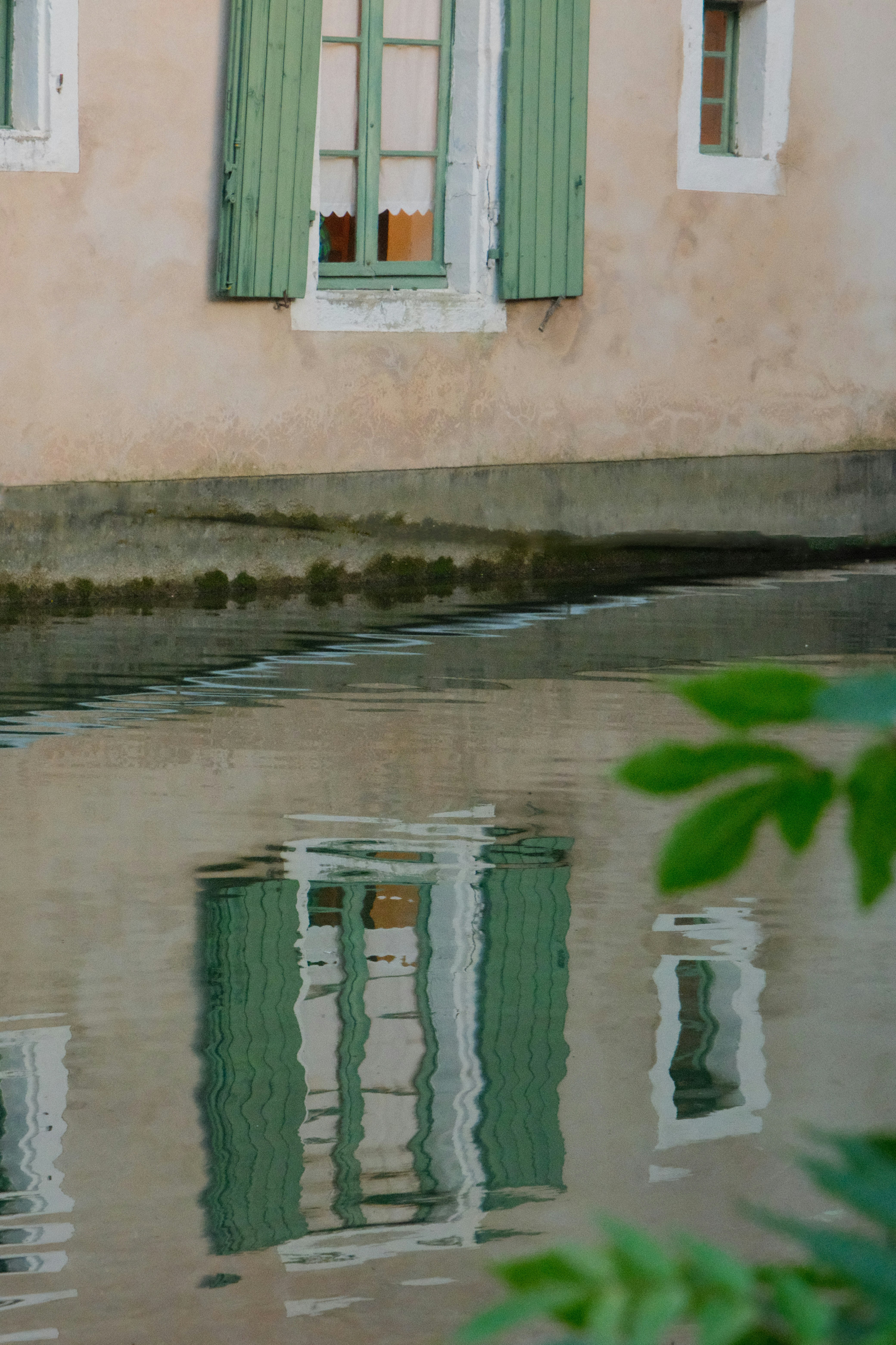 Green-Windowed Facade Reflections over Quiet Canal