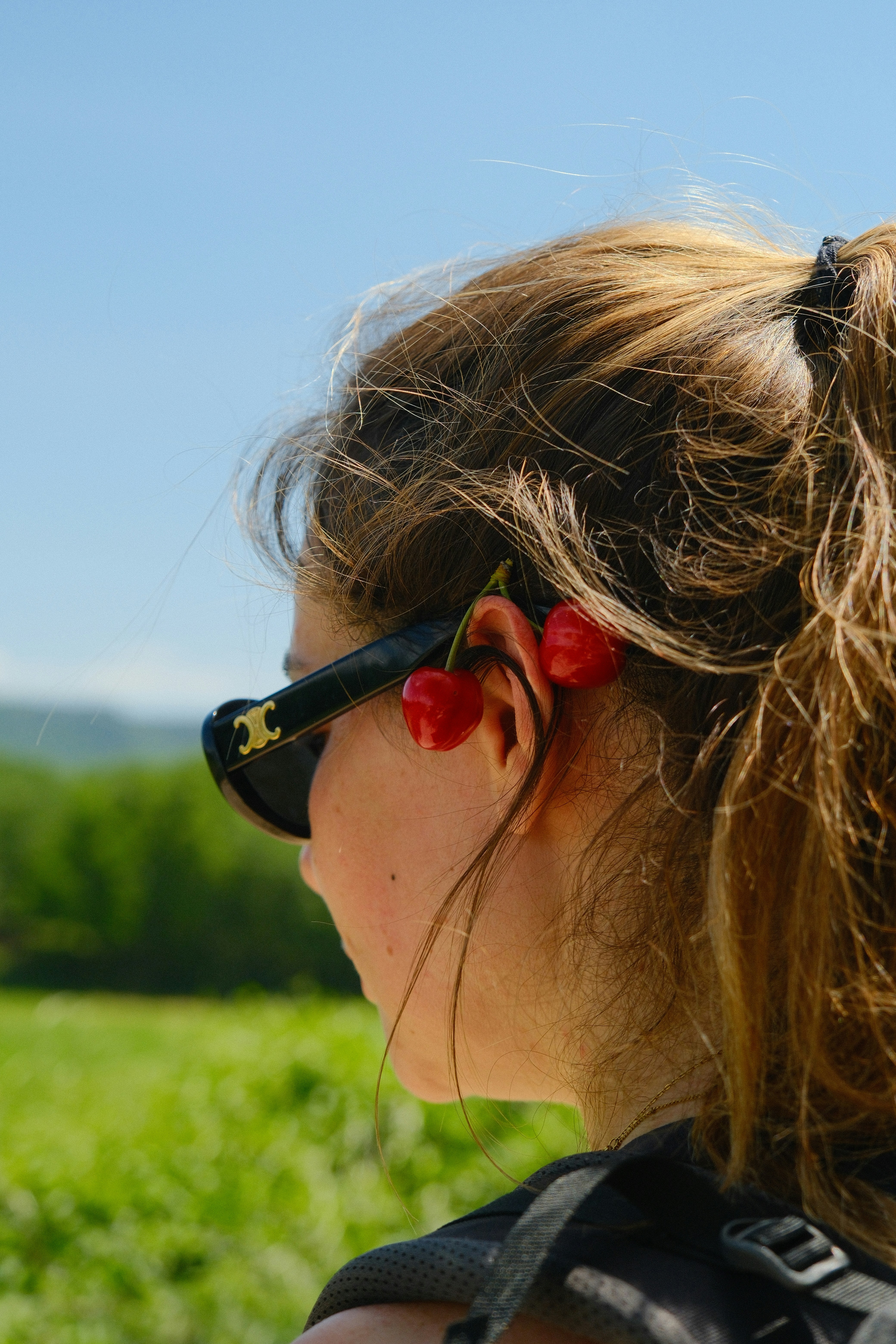 Sunlit Portrait in Sunglass Frame: A Side View with Red Earbuds