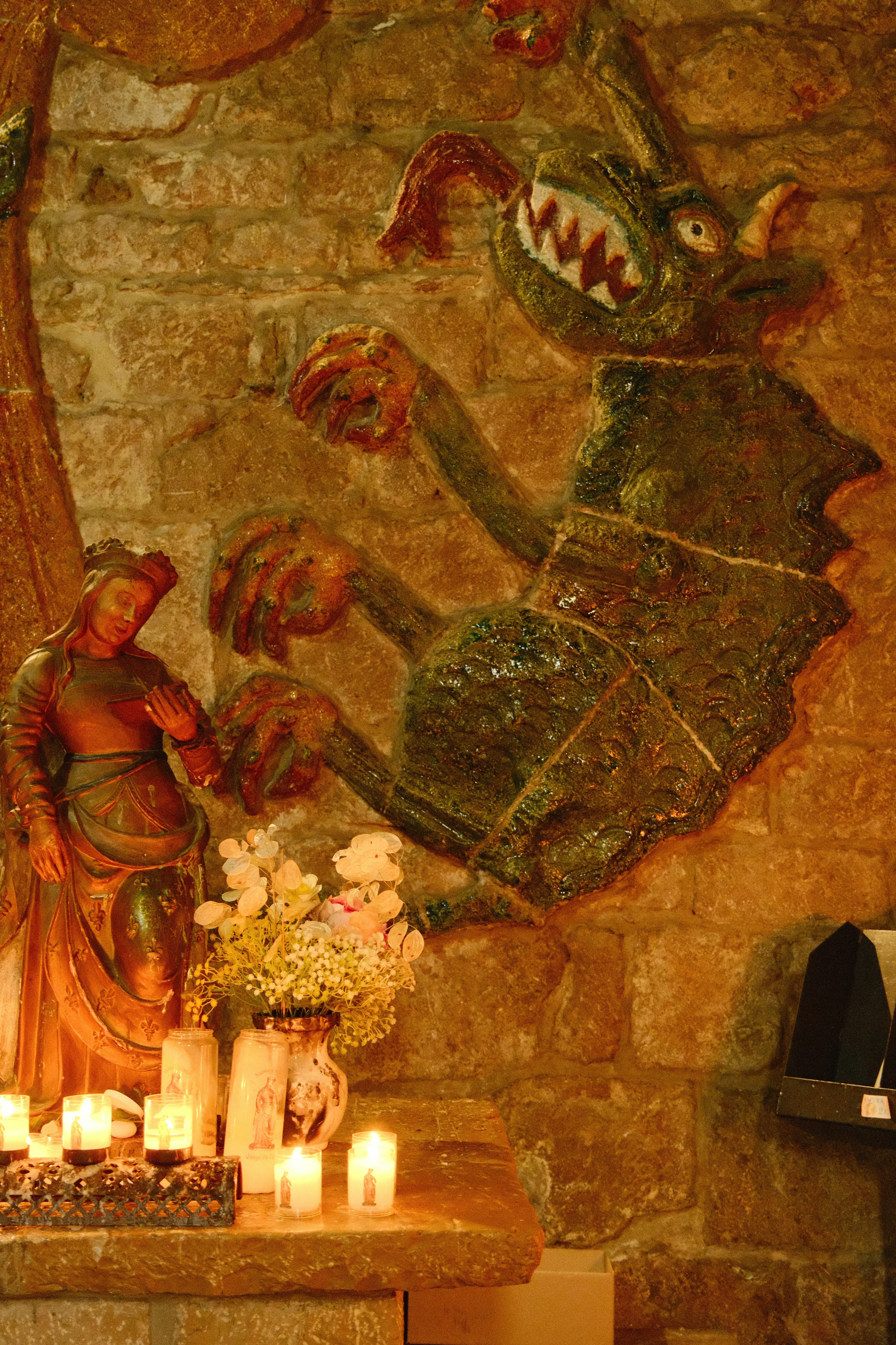 Dragon mural over a rustic shrine: candlelit altar beneath a stone wall