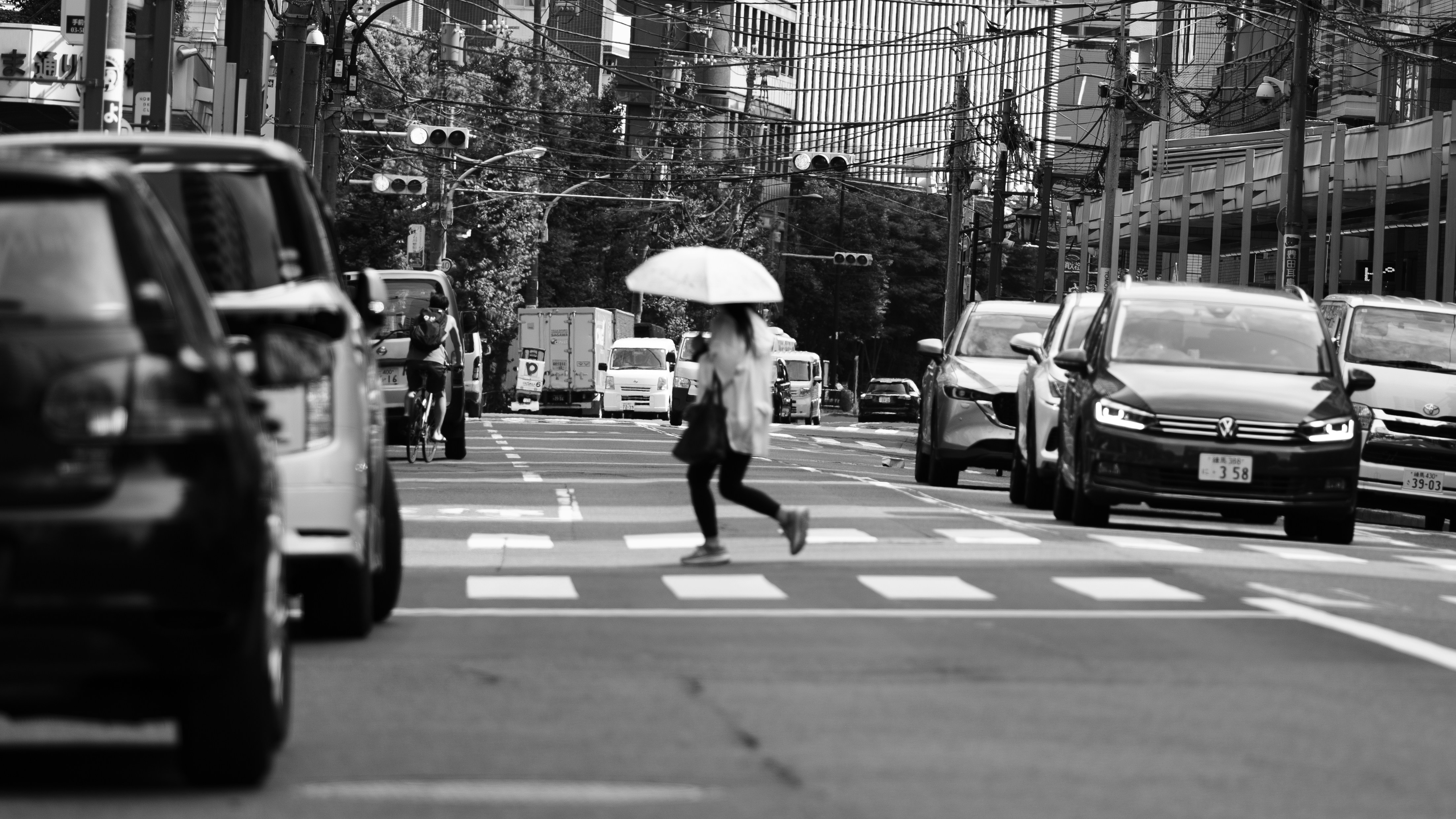 Crosswalk Moment: A Pedestrian with an Umbrella Traverses the City Pulse
