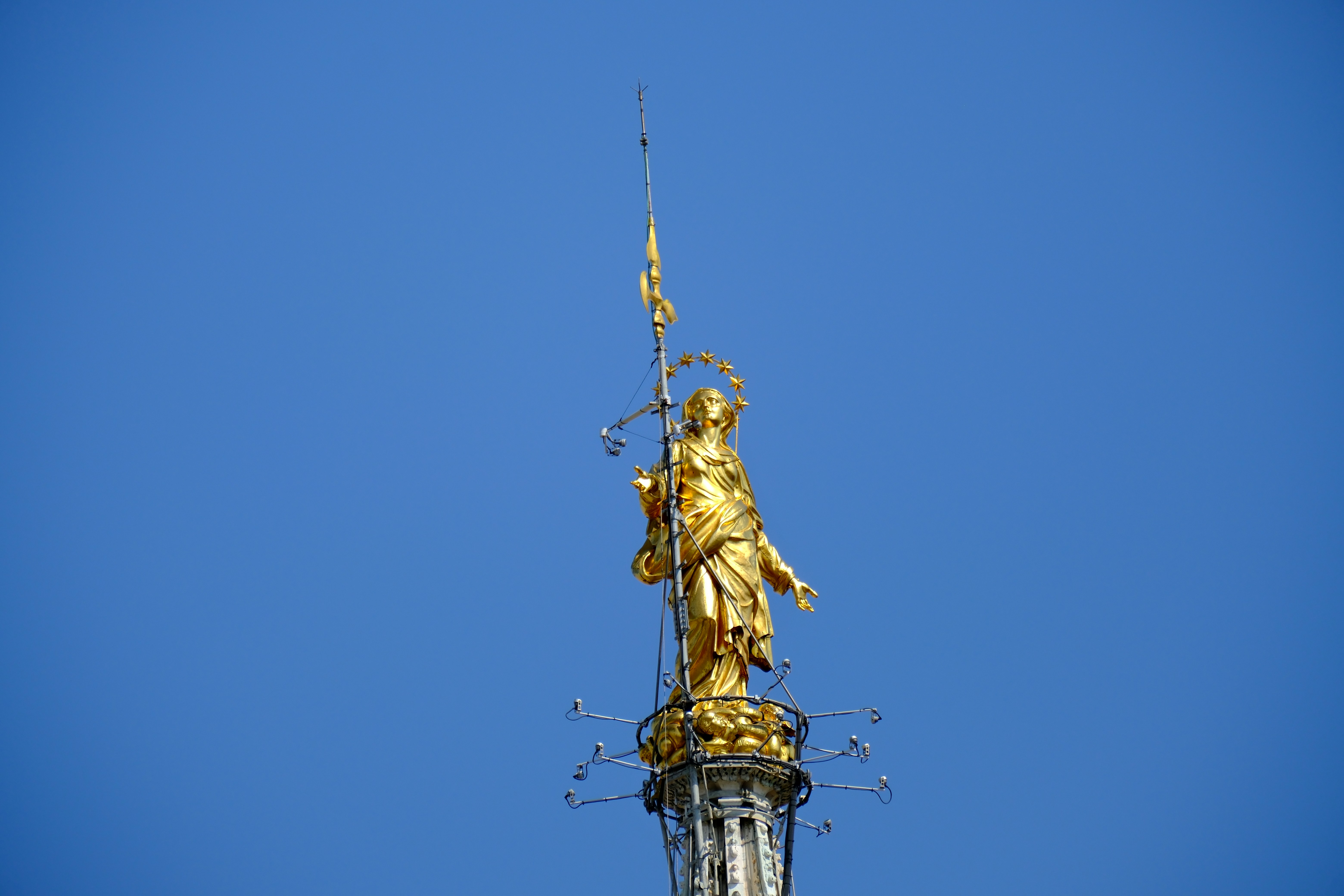 Golden statue atop a spire against a clear blue sky