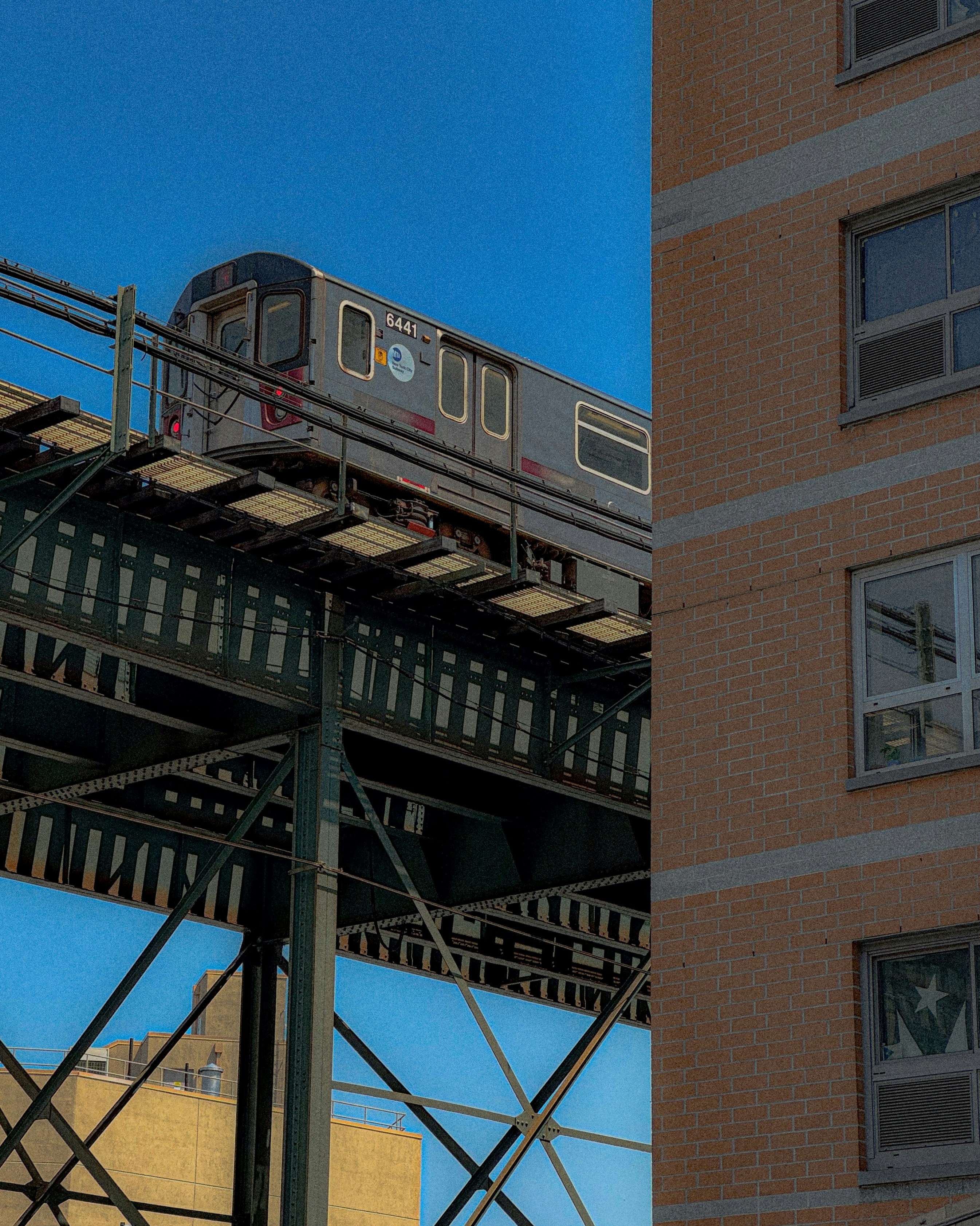Under the Steel Sky: Elevated Train Crossing a Brick Face