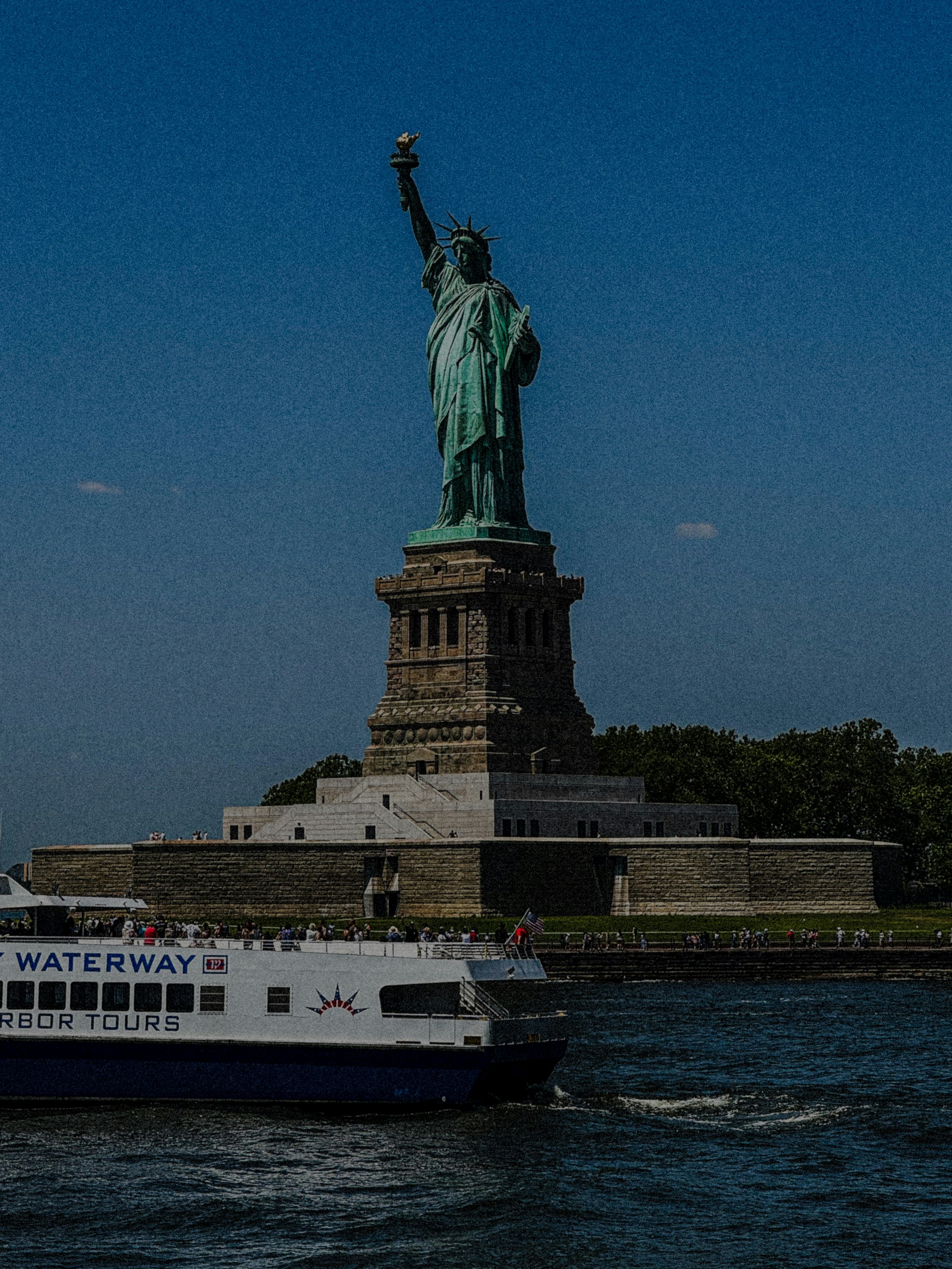Statue of Liberty over the Hudson: ferry glides by at dusk