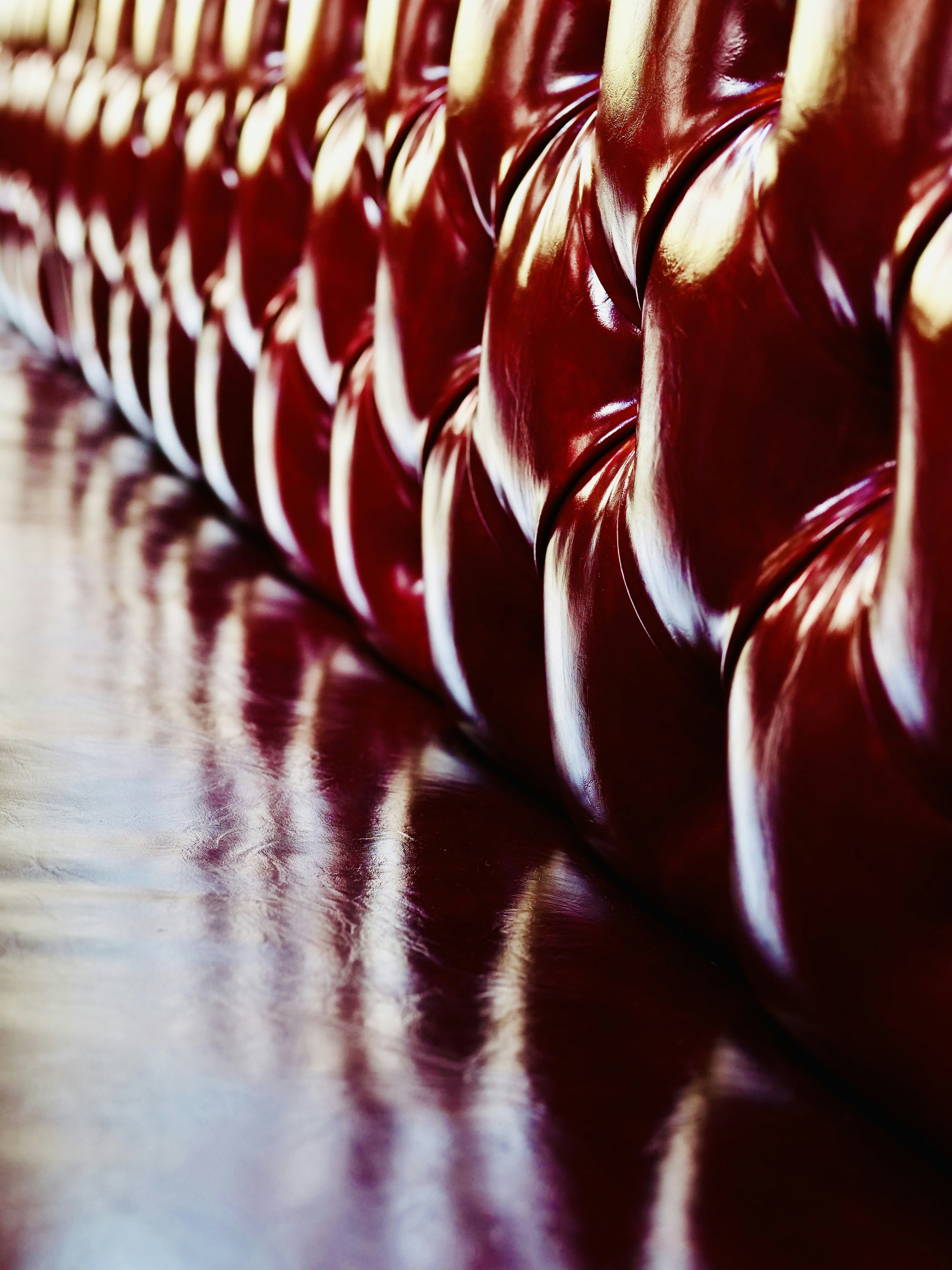 Glossy Red Upholstery Row: a close-up of tufted leather reflections
