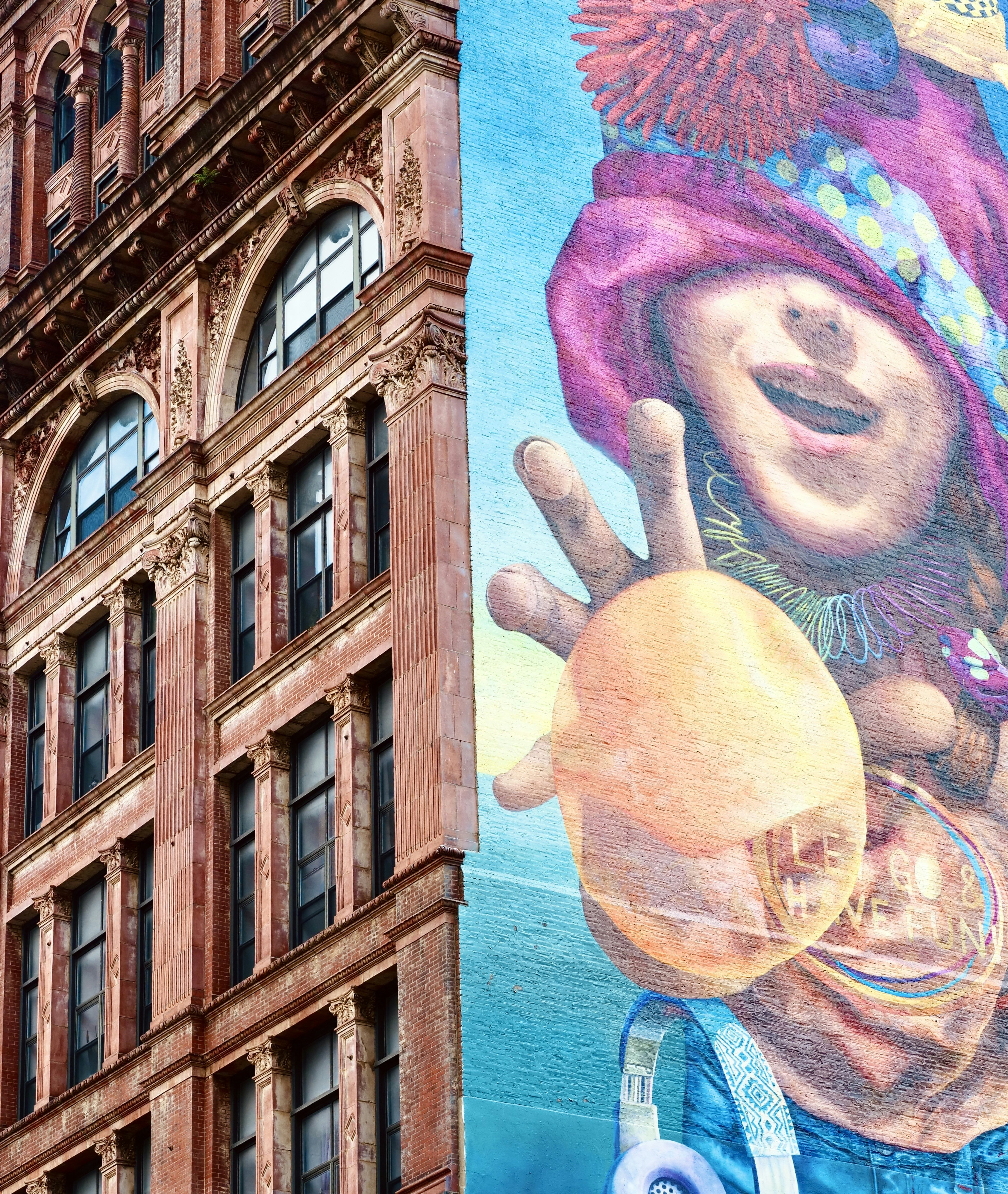 Colorful mural on brick facade: a cheerful clown reaching toward the viewer