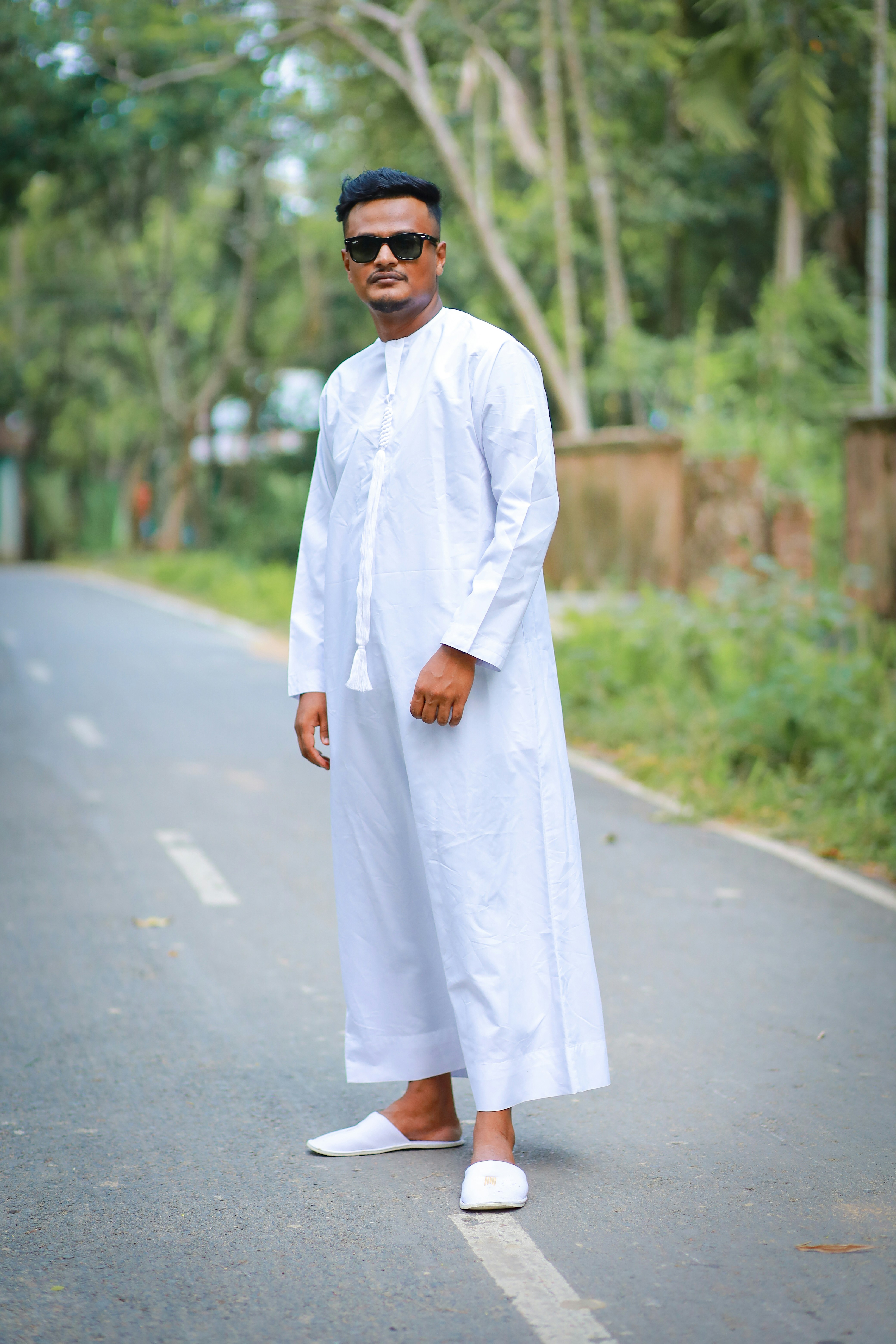 Man in white traditional attire and sunglasses on a road