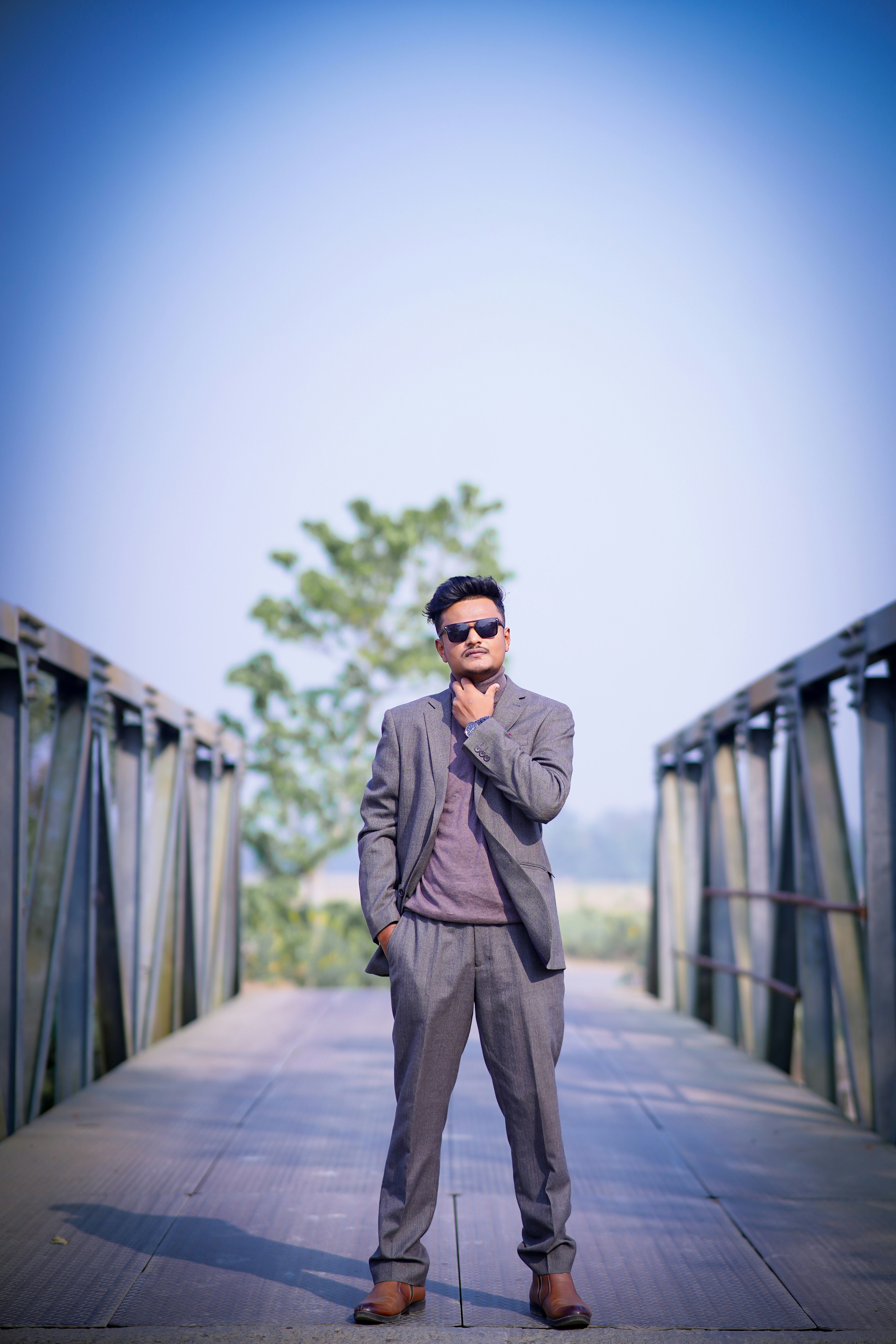 Sleek Confidence: A Man in a Sharp Suit Stands Center Stage on a Bridge