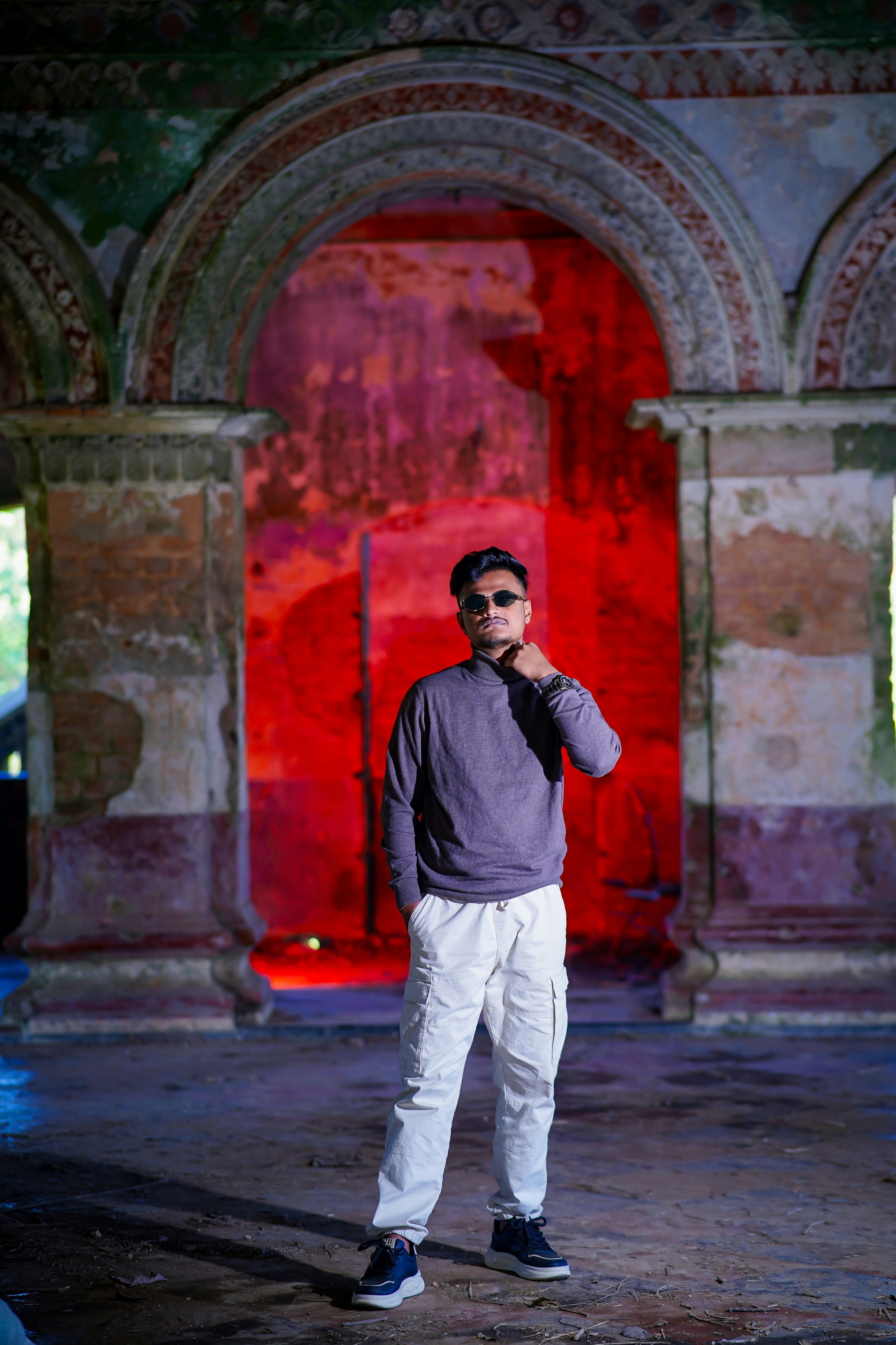 Portrait under crimson arch: a man in a purple hoodie stands in front of a historic doorway