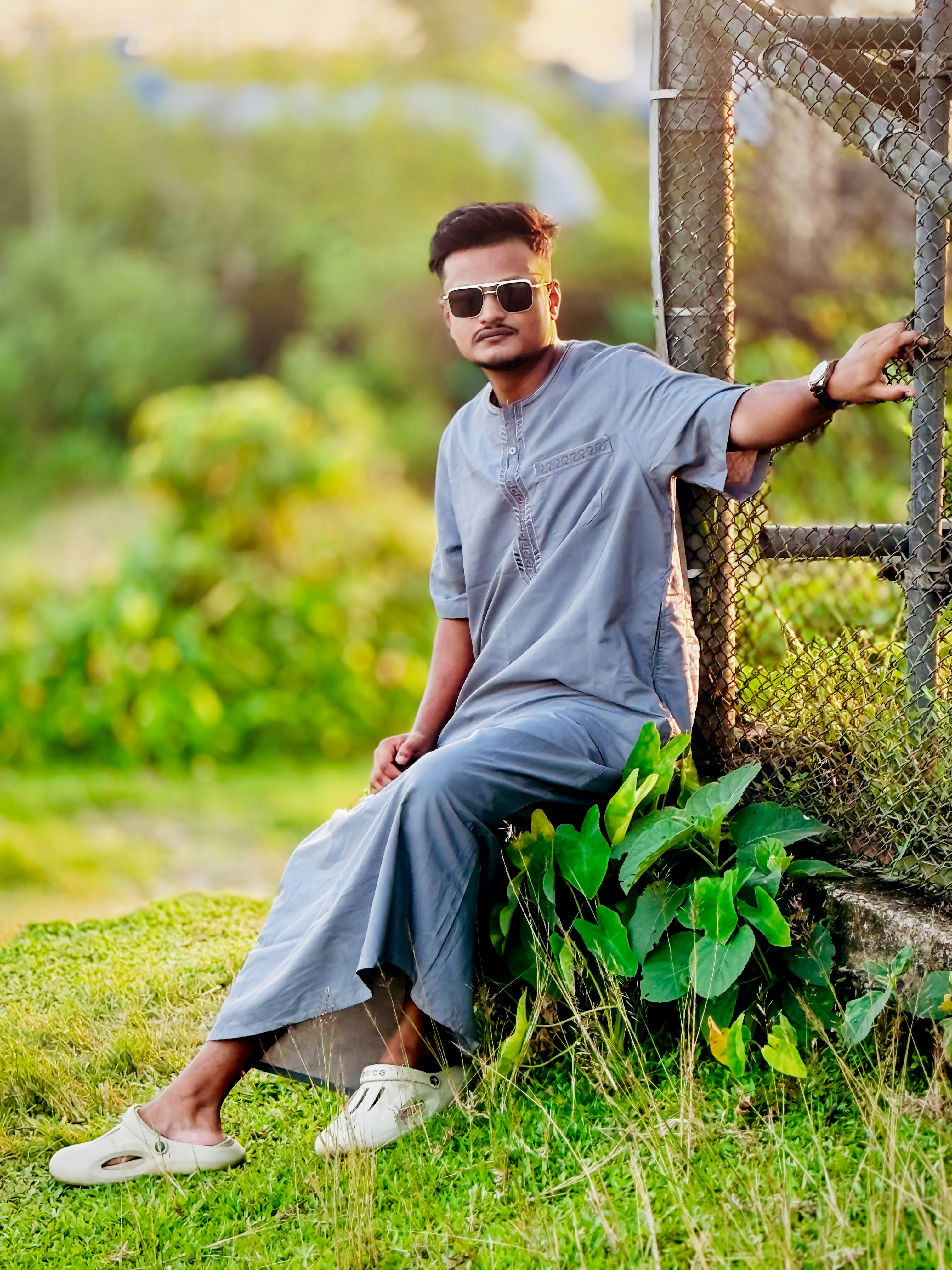 Relaxed Confidence: Man in a Blue Kurta Lounges by the Fence