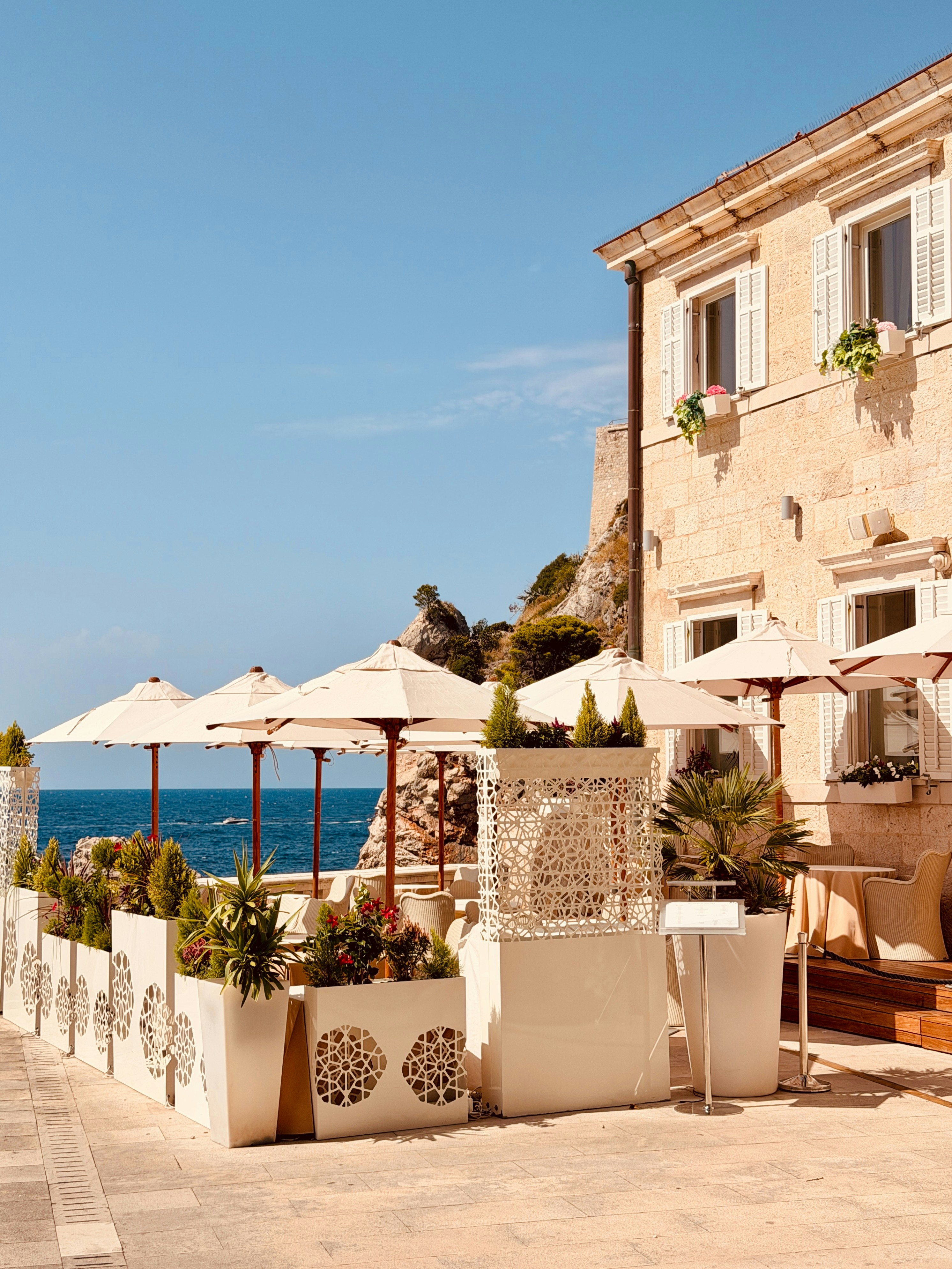 Sunlit Terrace by the Mediterranean: White Stone, Sea Breeze, and Umbrella Rows