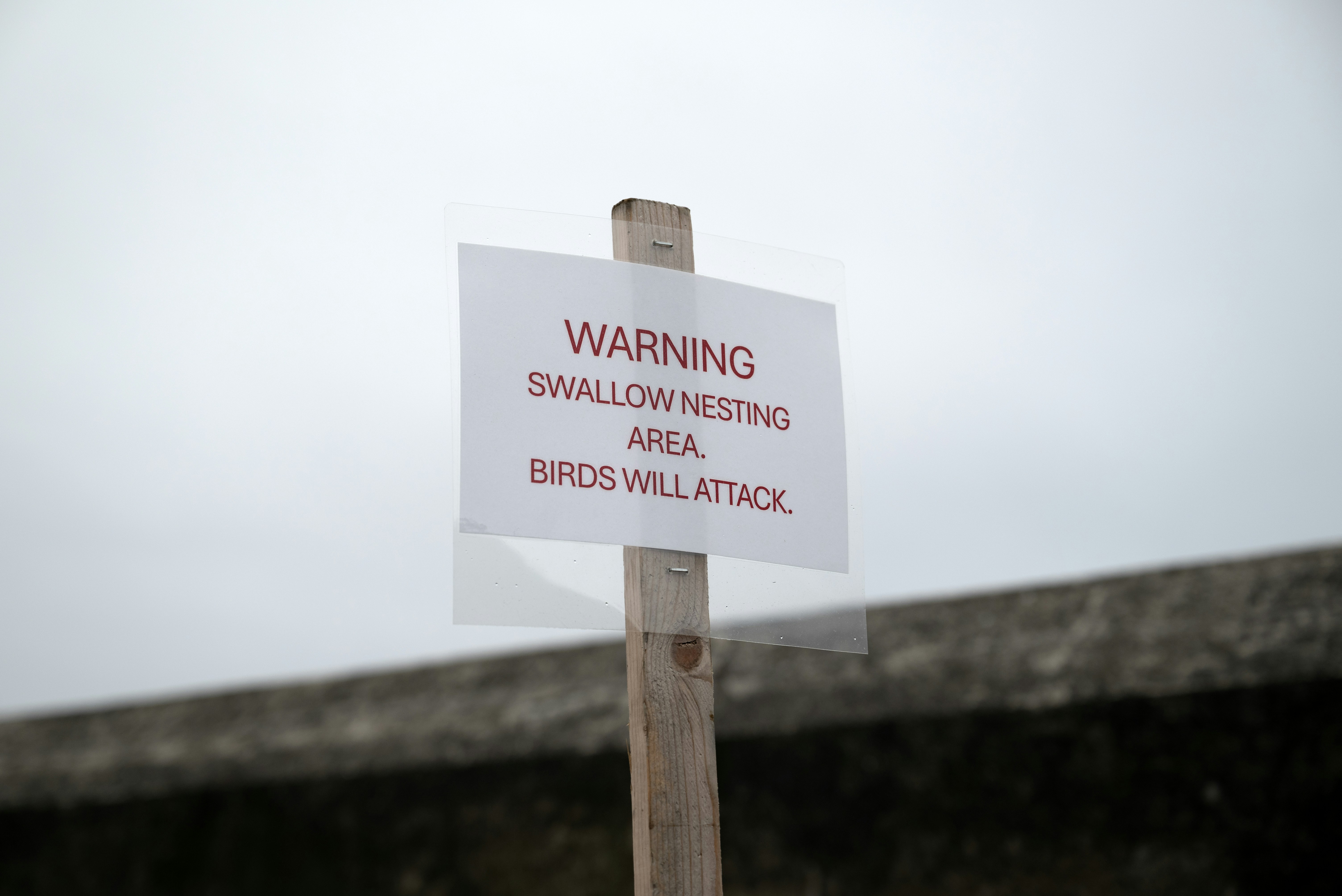 Warning sign on a wooden post over a weathered barrier