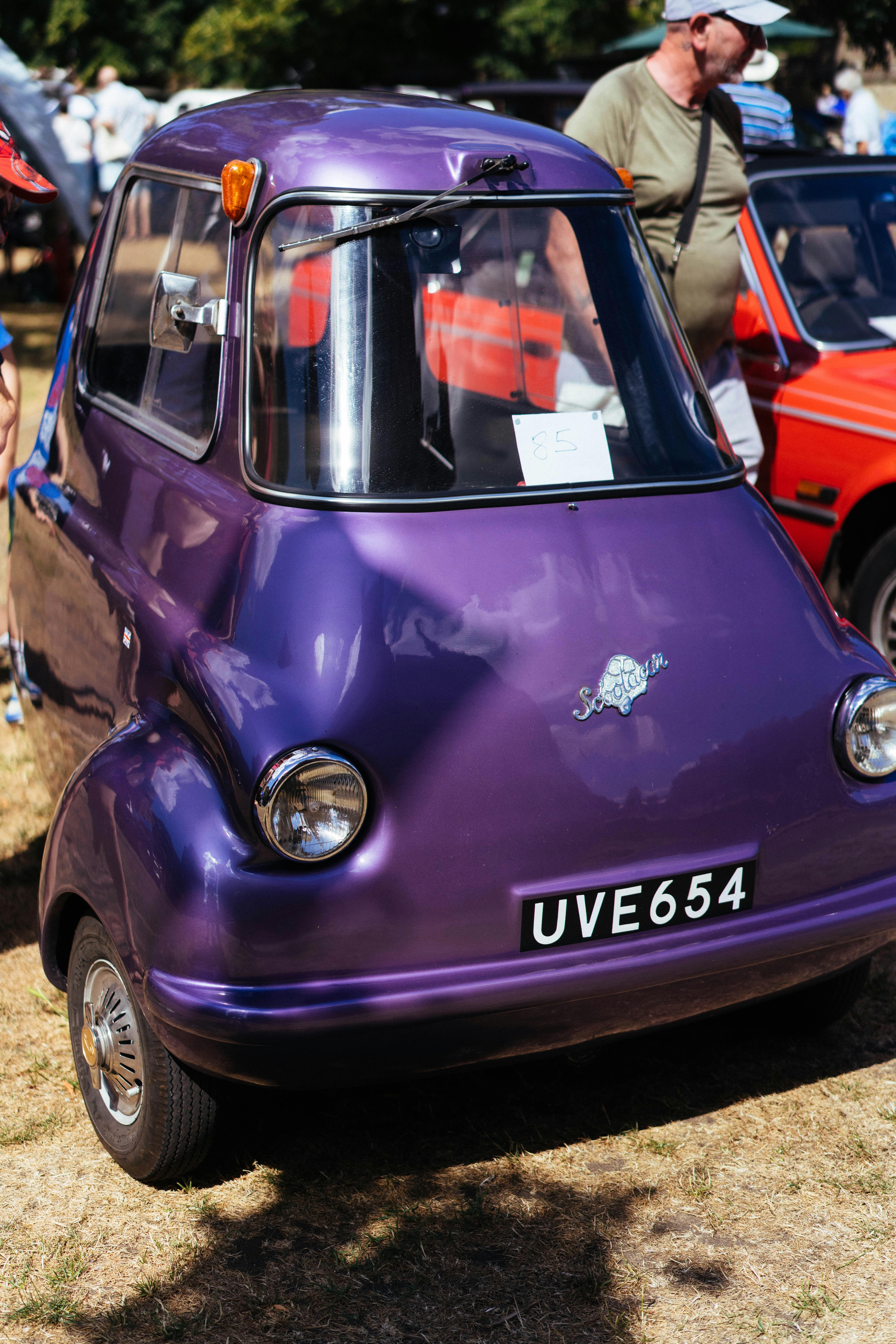 Purple microcar at a sunlit classic car show