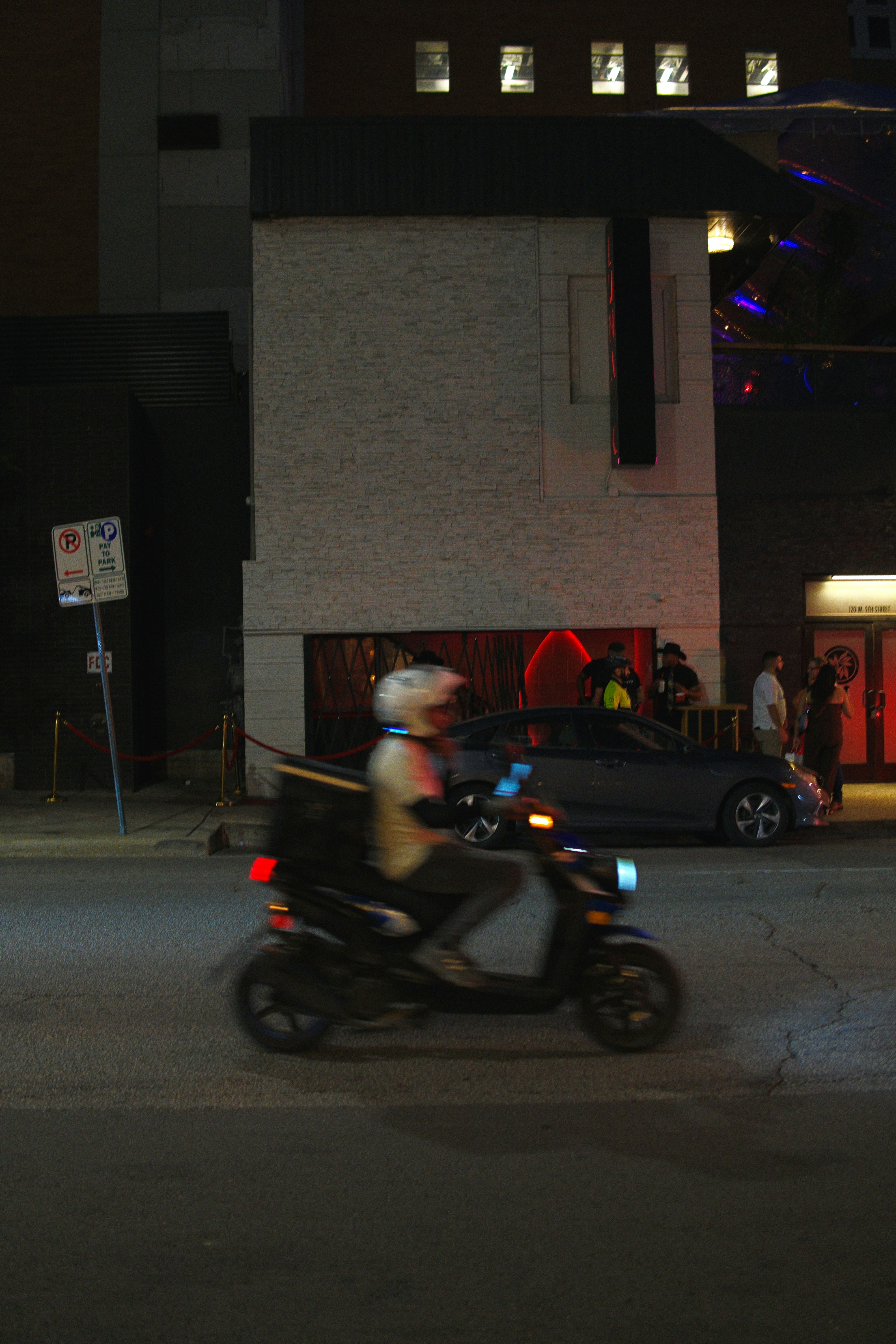 Night Street Blur: A Motorbike Surges Past a Quiet storefront