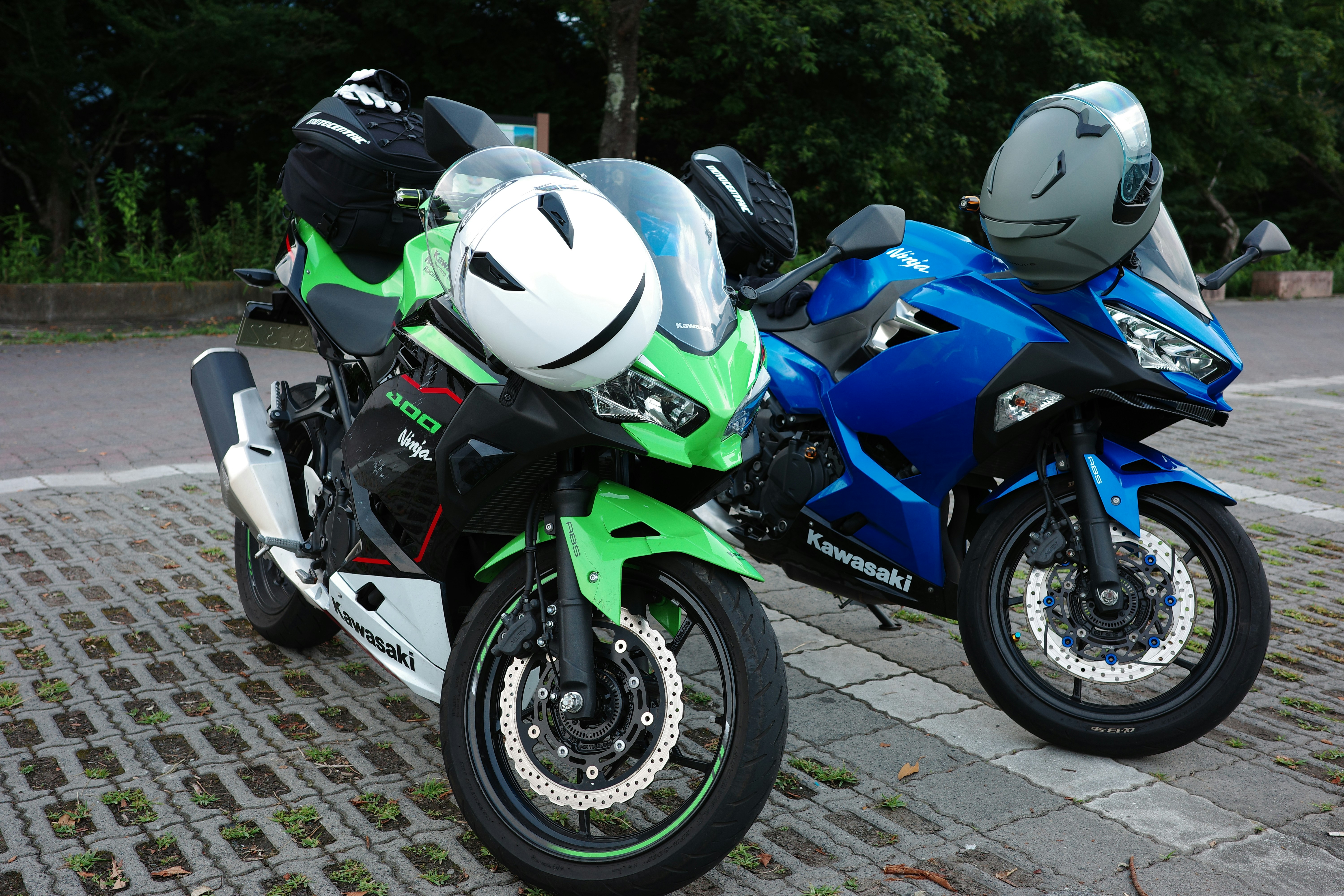 Twin Streak: Green and Blue Kawasaki Stand Clubbed in the Parking Lot