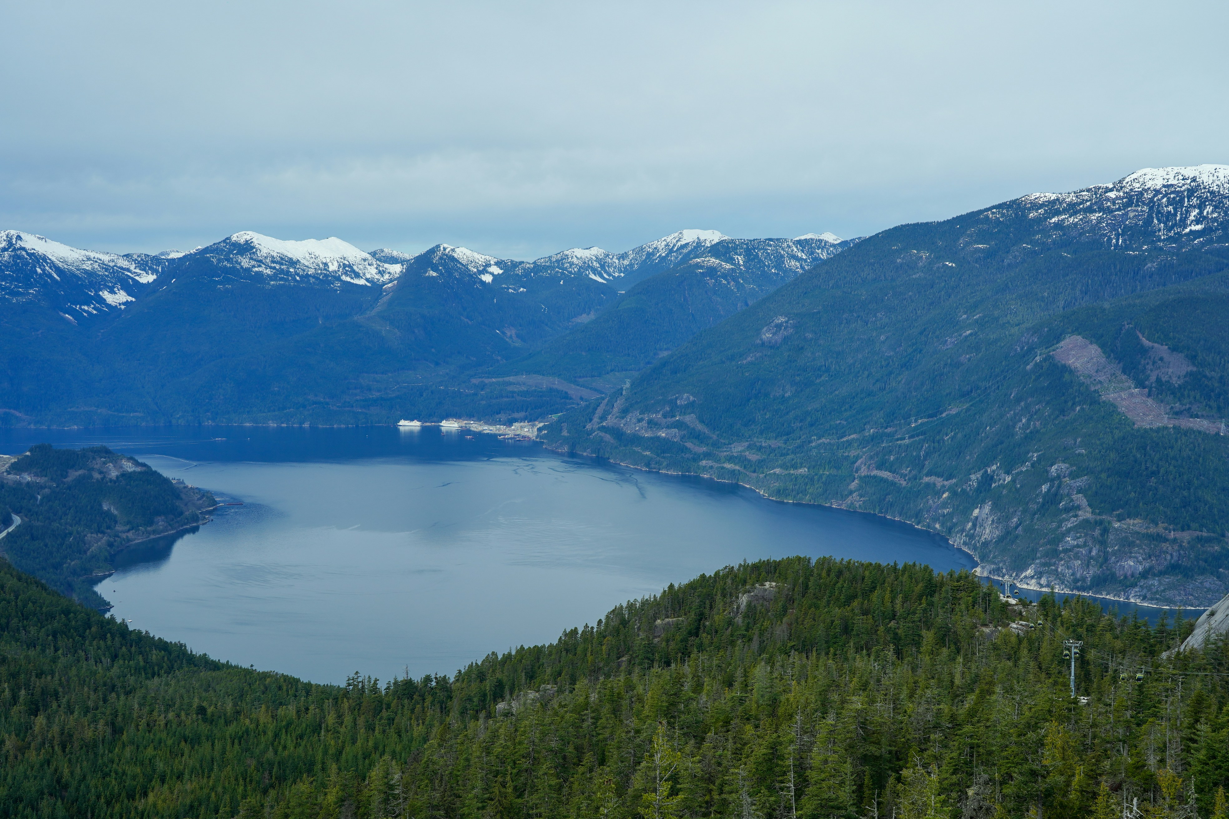 Snow-kissed peaks cradle a tranquil fjord below