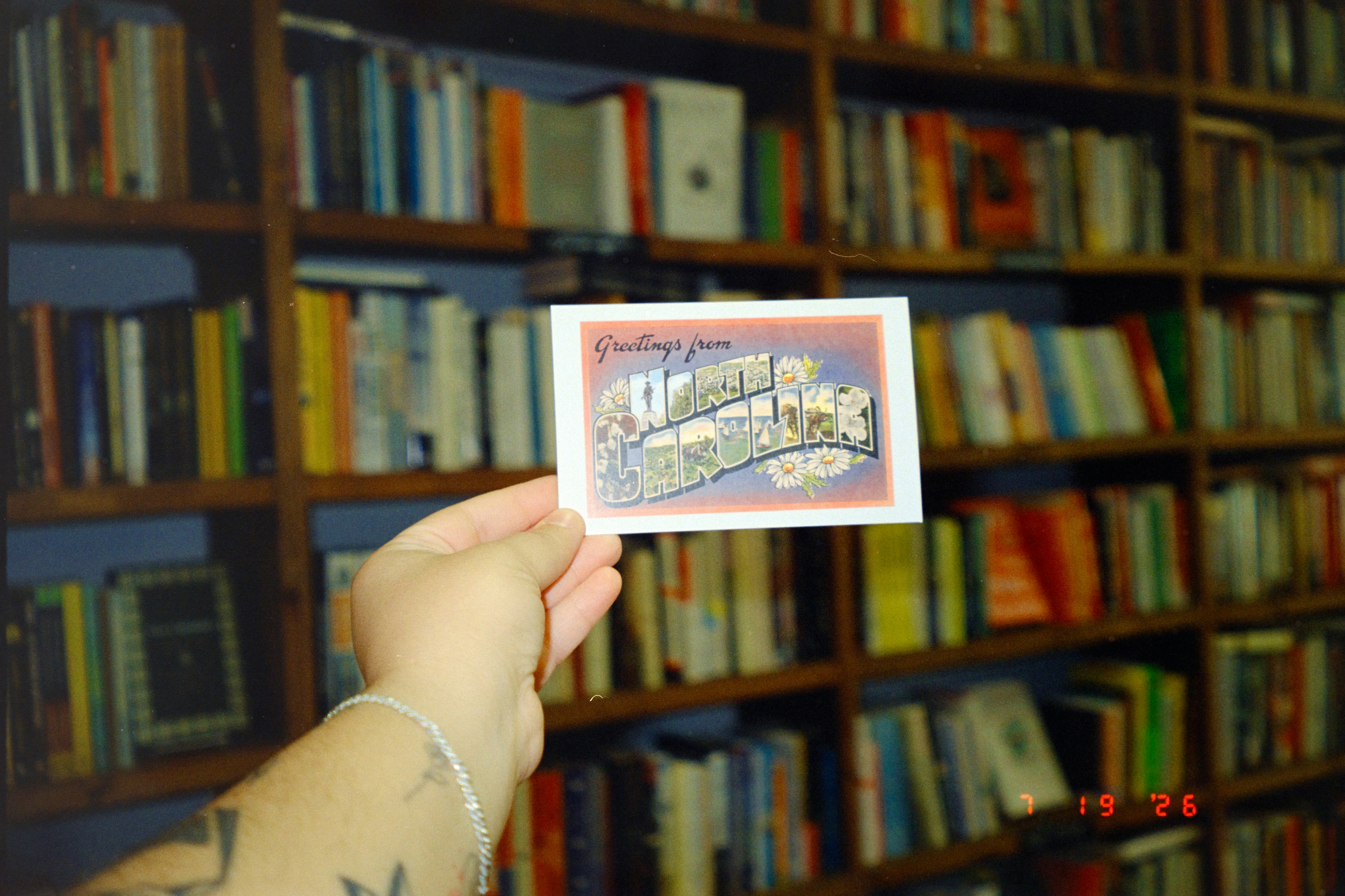 A Handheld Greeting Card Looms Over Bookshelves