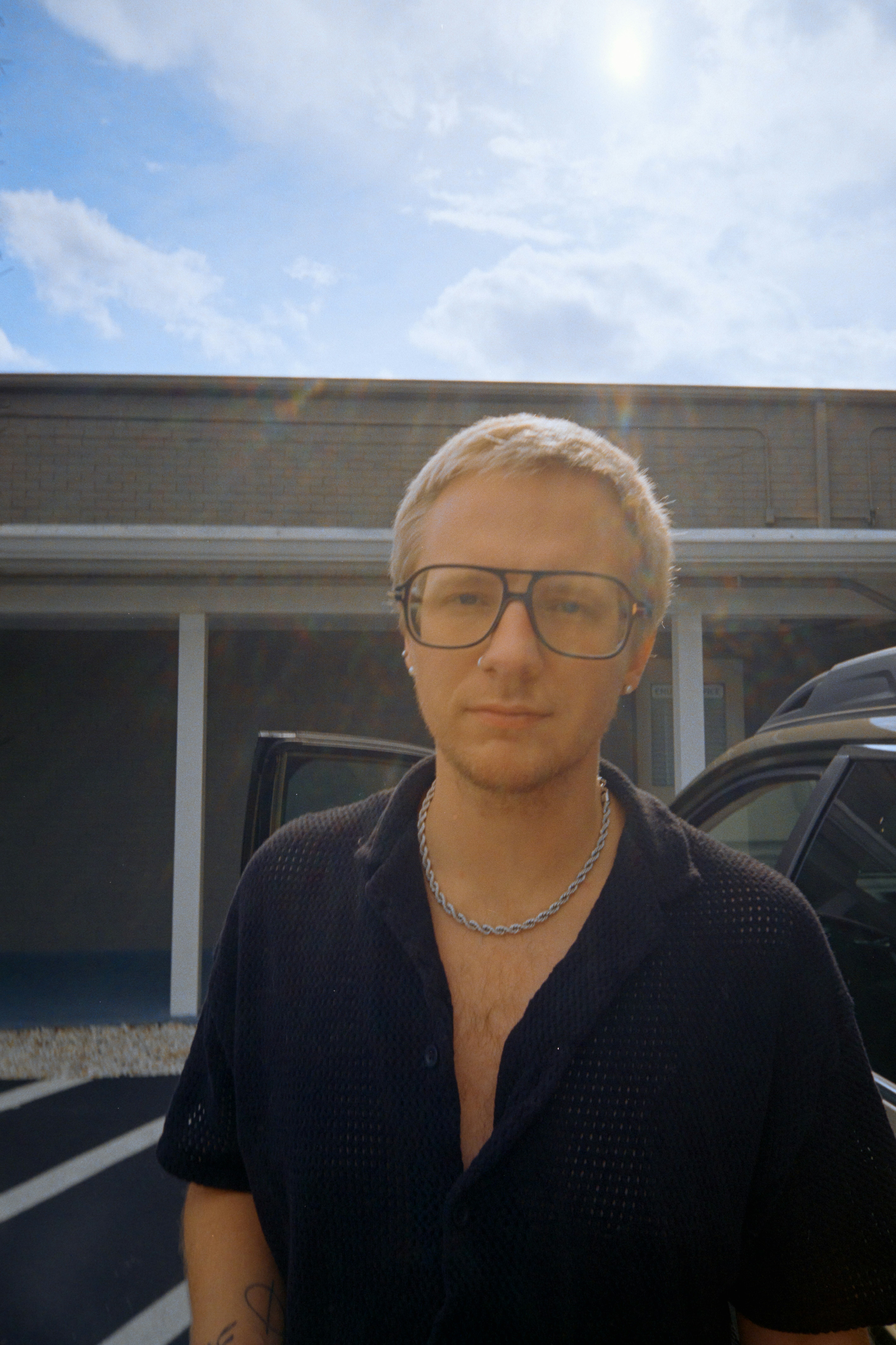 Sunlit portrait in a casual black shirt with oversized glasses