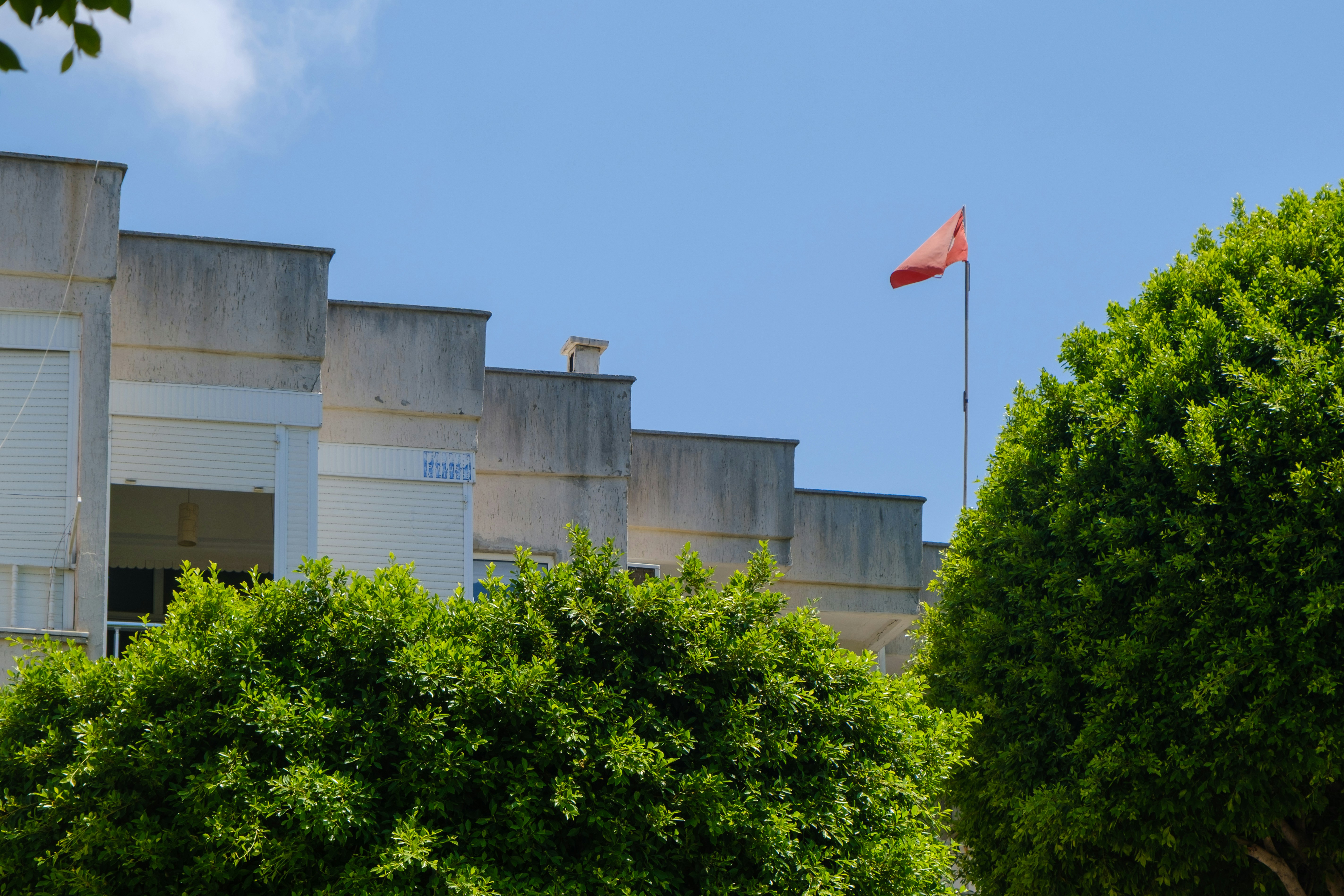Red Flag Above a Quiet Campus Skyline
