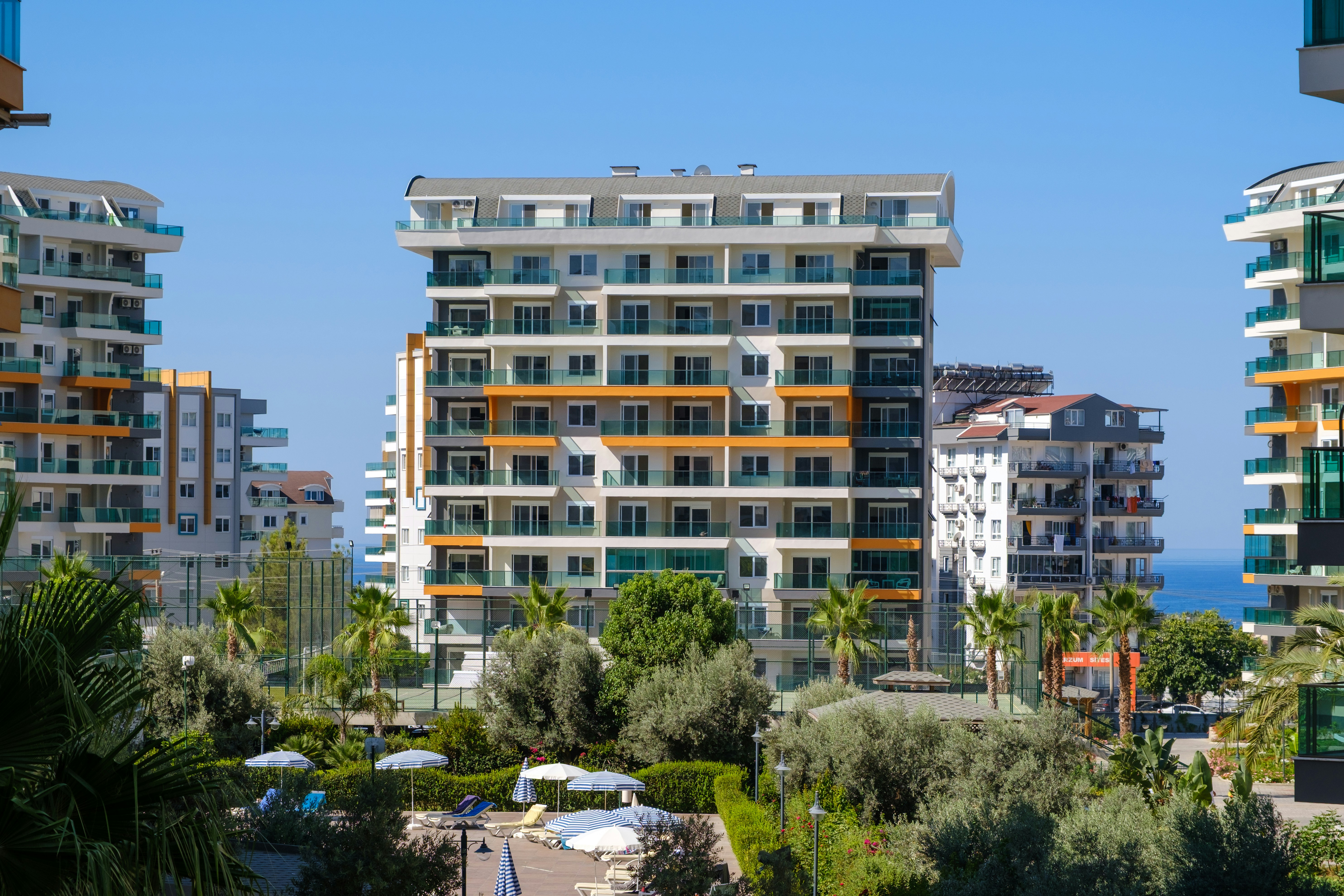 Sunlit Coastal Complex: Modern Towers Framed by Palm Oasis