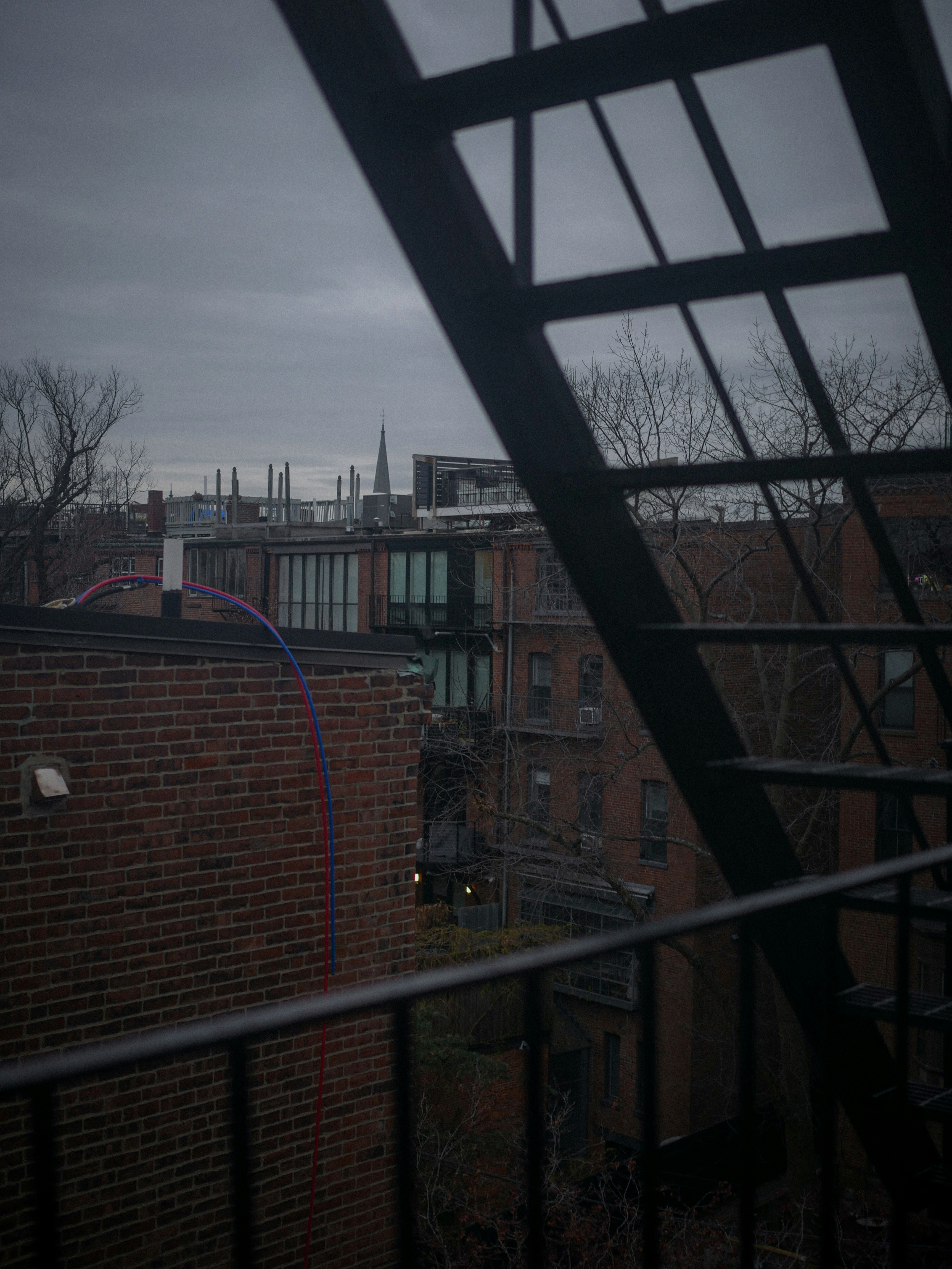 Rooftop View through a Fire Escape: City Lines and Bricks