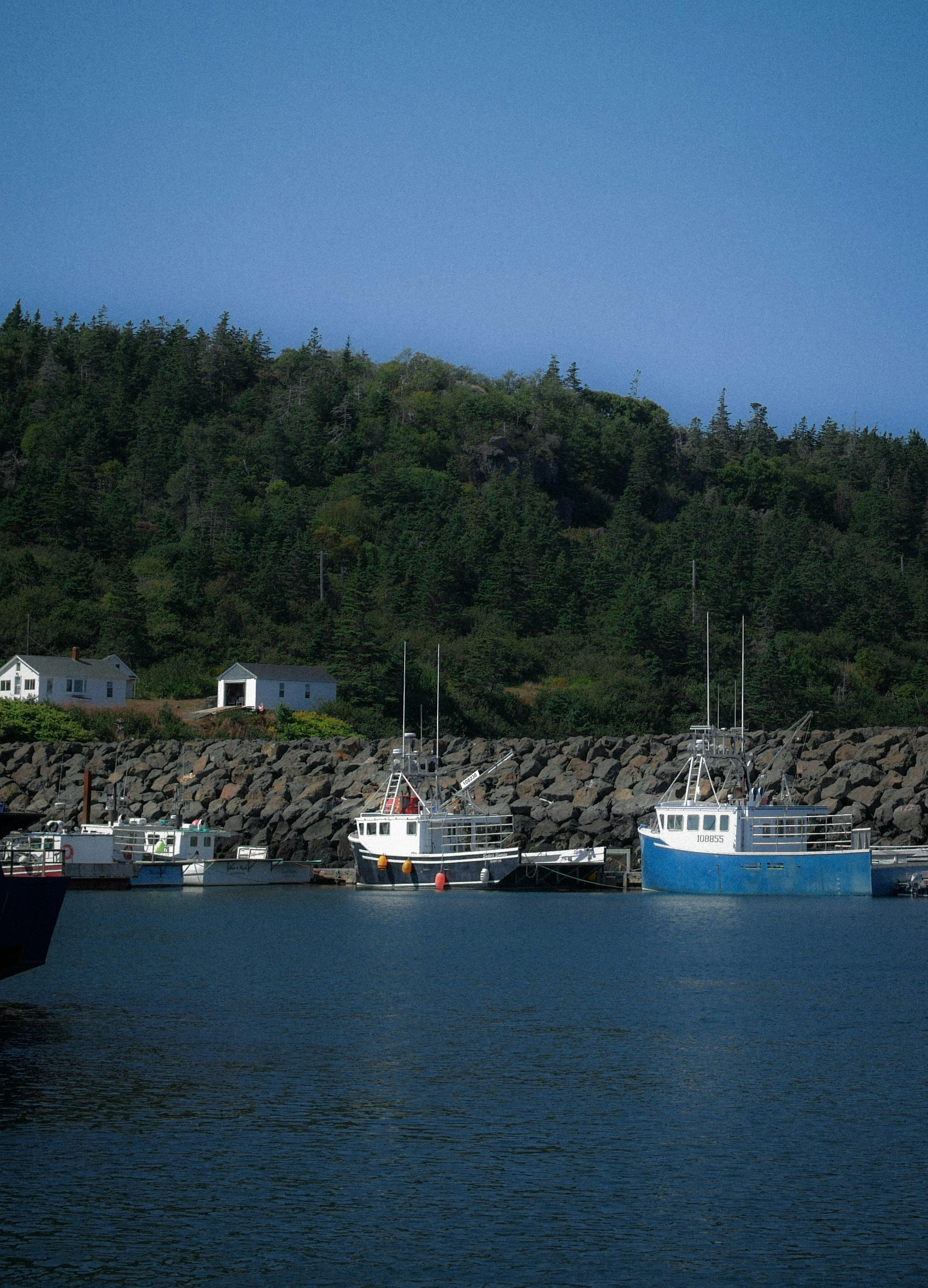 Harbor Boats at Dusk: Boats Rest Along a Stone Breakwater