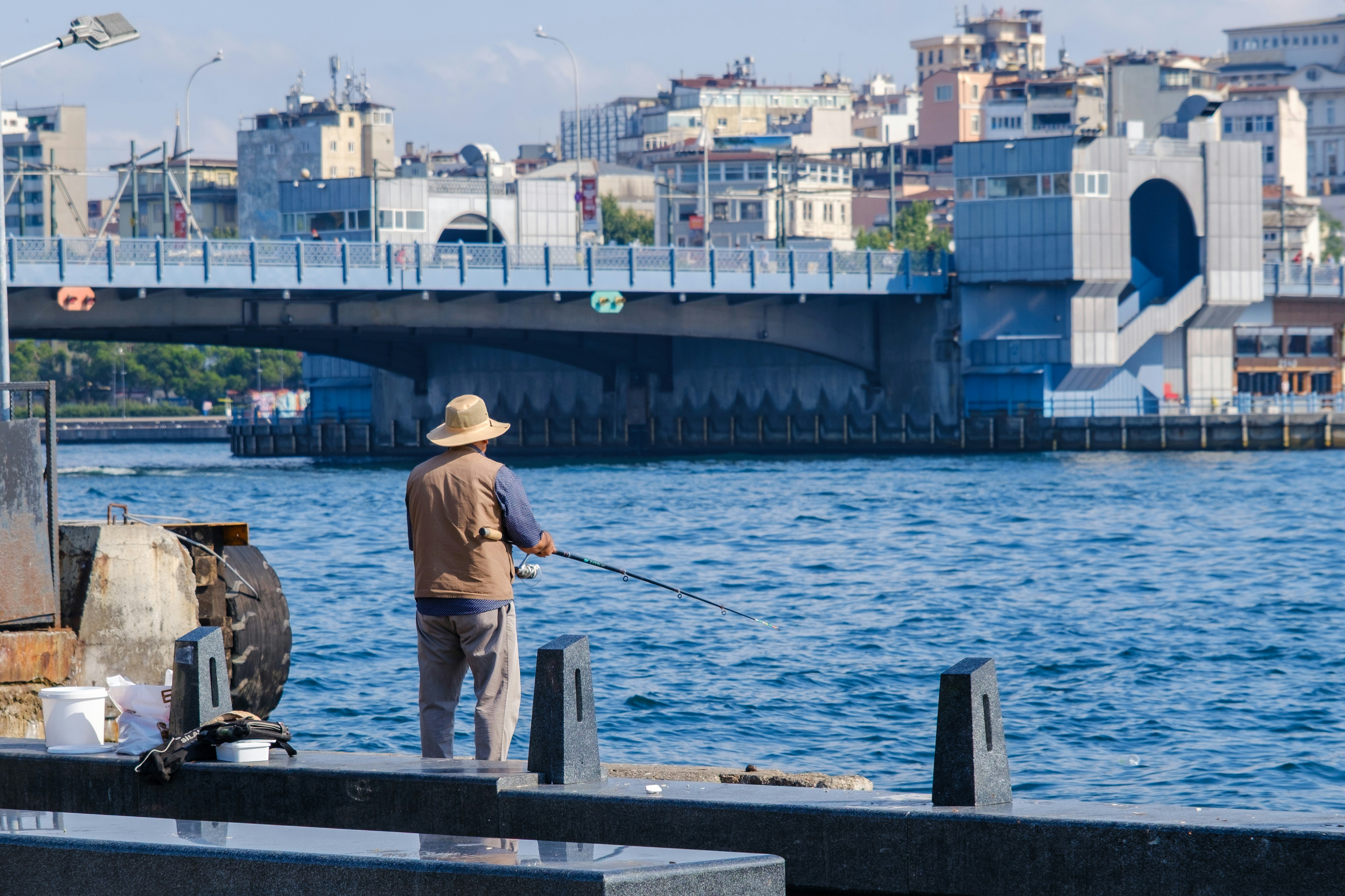 The Riverside Angler Beneath a Pier of Blue Bridges