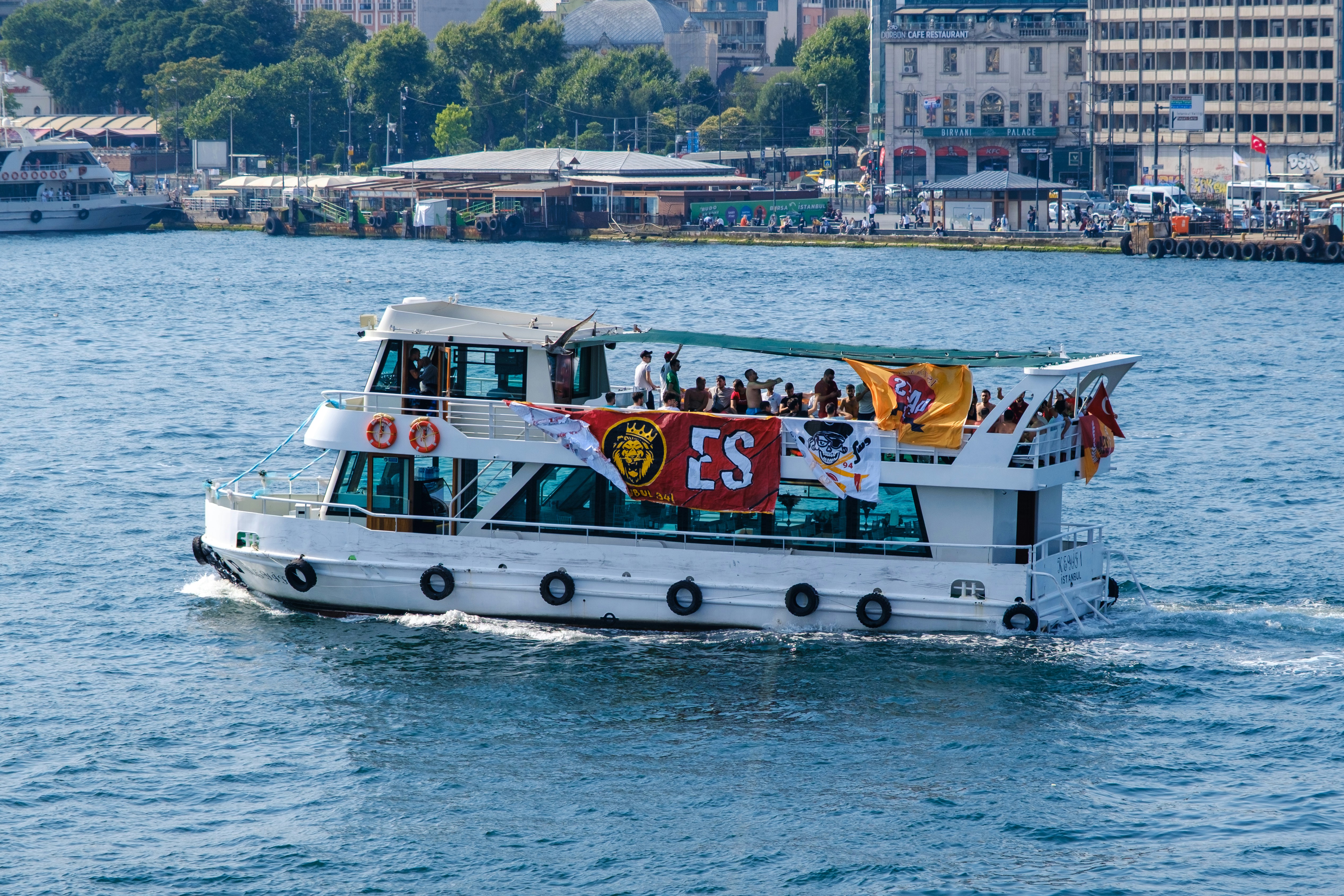 Sunlit Harbor Tourer: A Passenger Vessel Draped in Color Sails Across Calm Blue