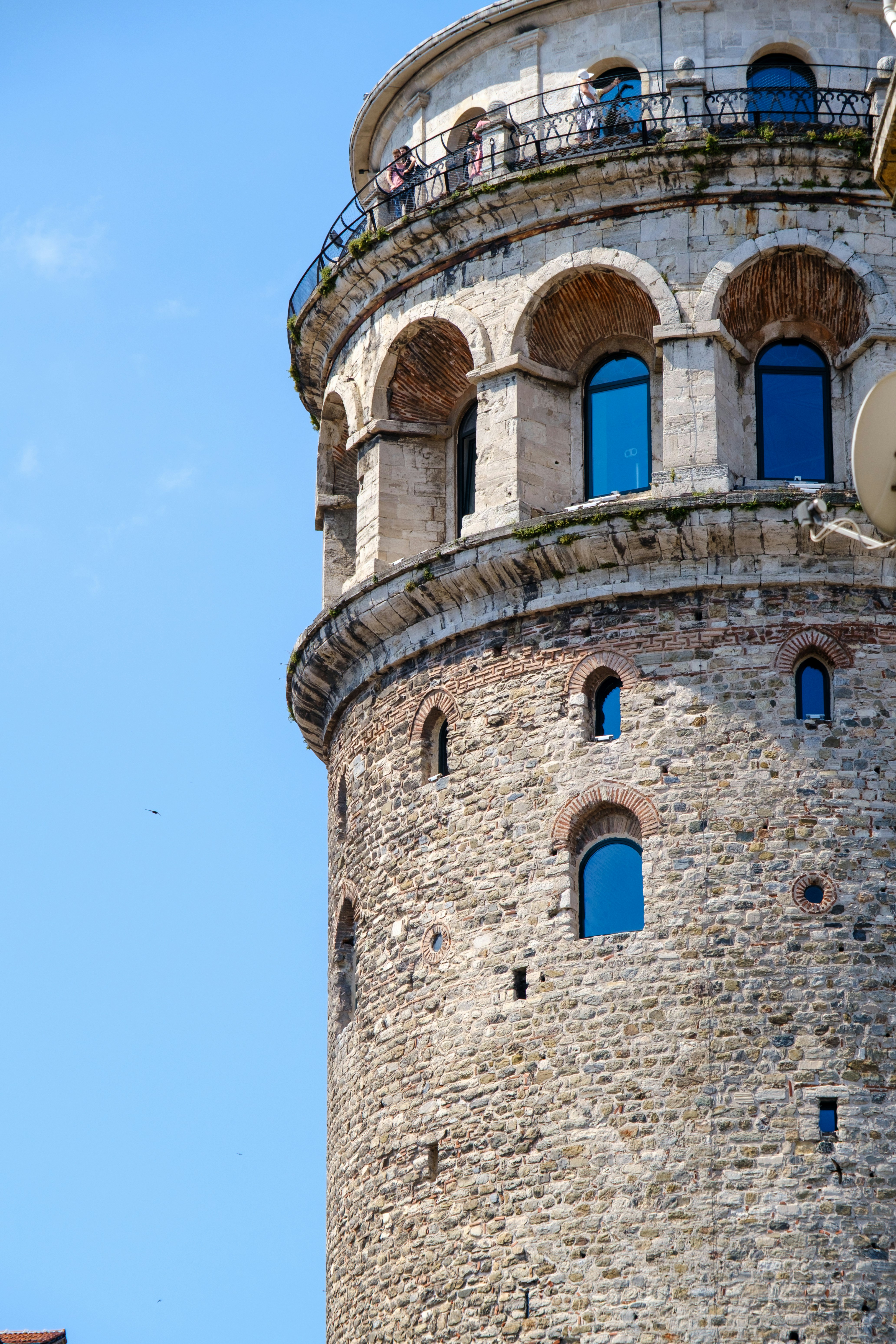 Towering Granite: A Sunny Historia in Stone with Onlookers at the Balcony