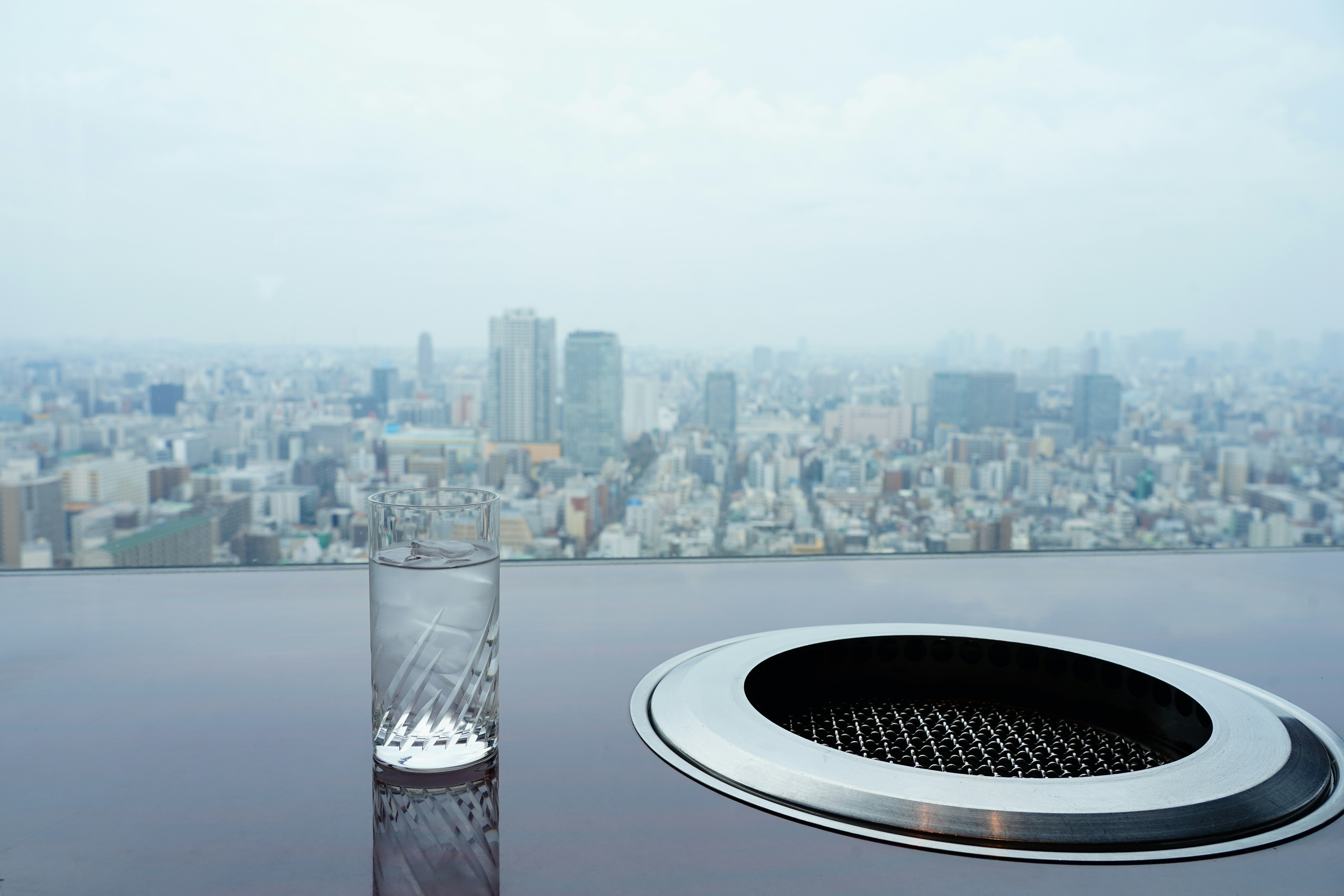 Urban Rooftop Moment: Glass, Fire Pit, and a Distant Cityscape