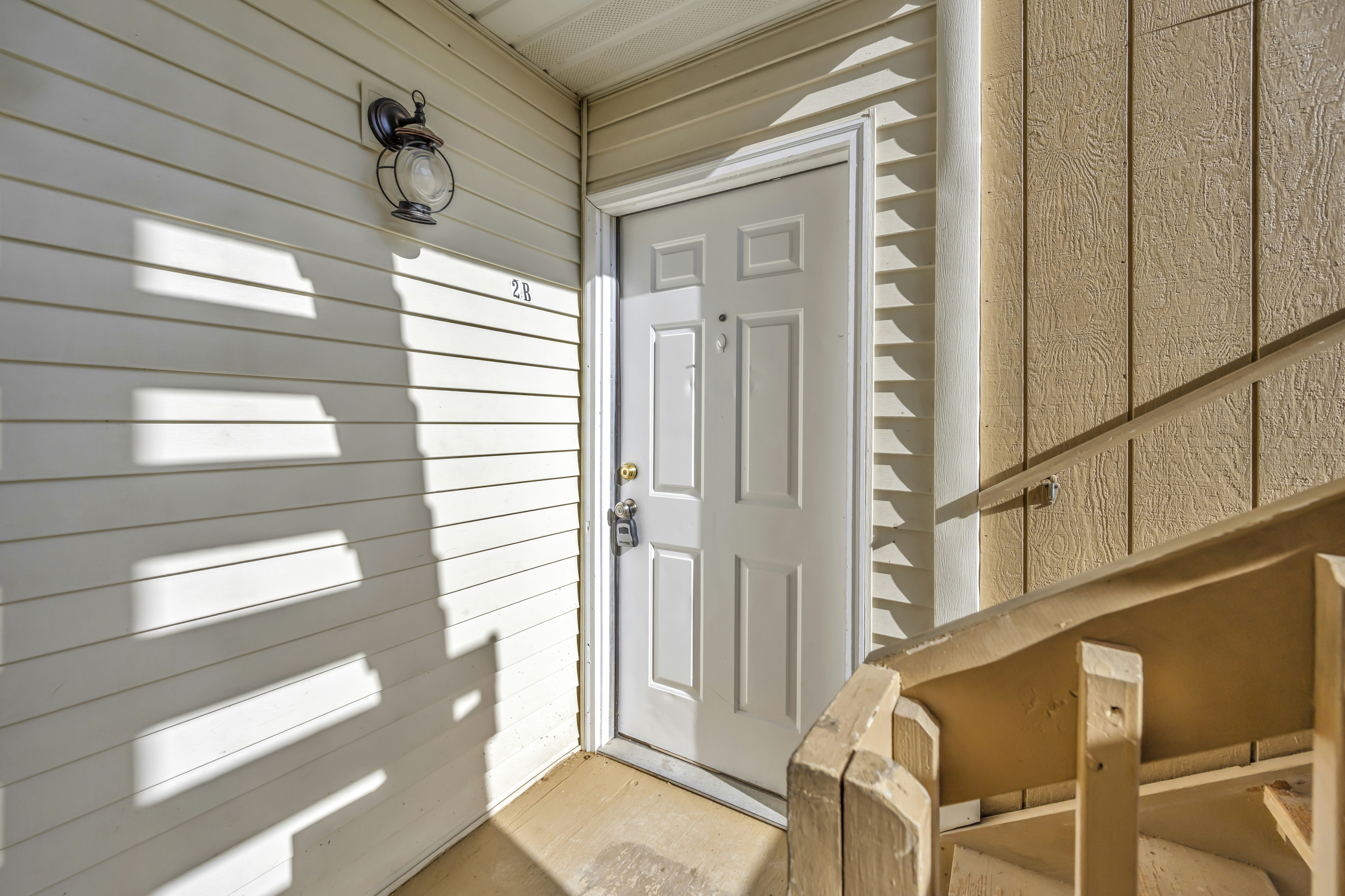 Sunlit Entryway with Shadowed Siding and Stairwell