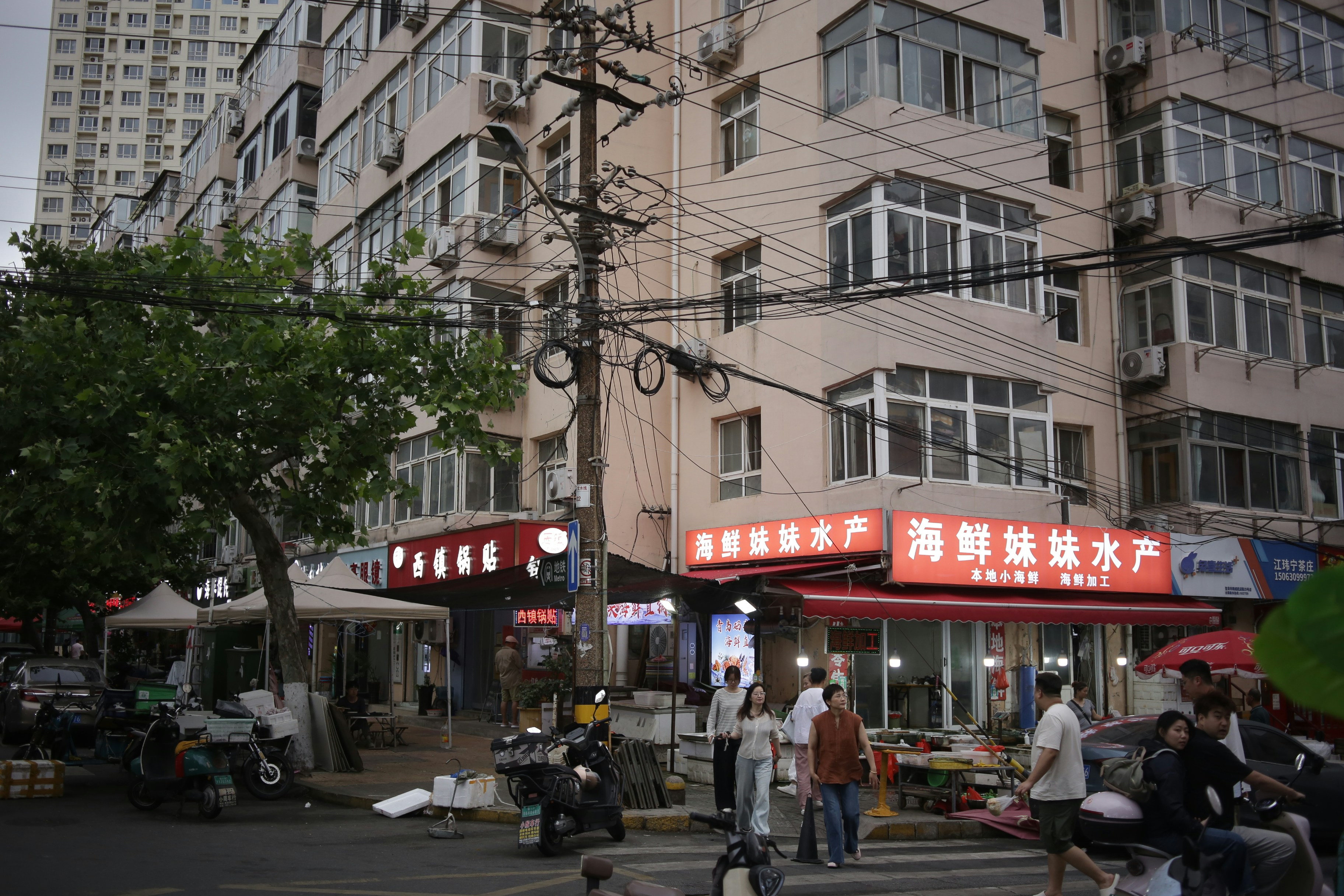 Urban Market Corridor: Faces, Signs and scooters under a peach apartment block