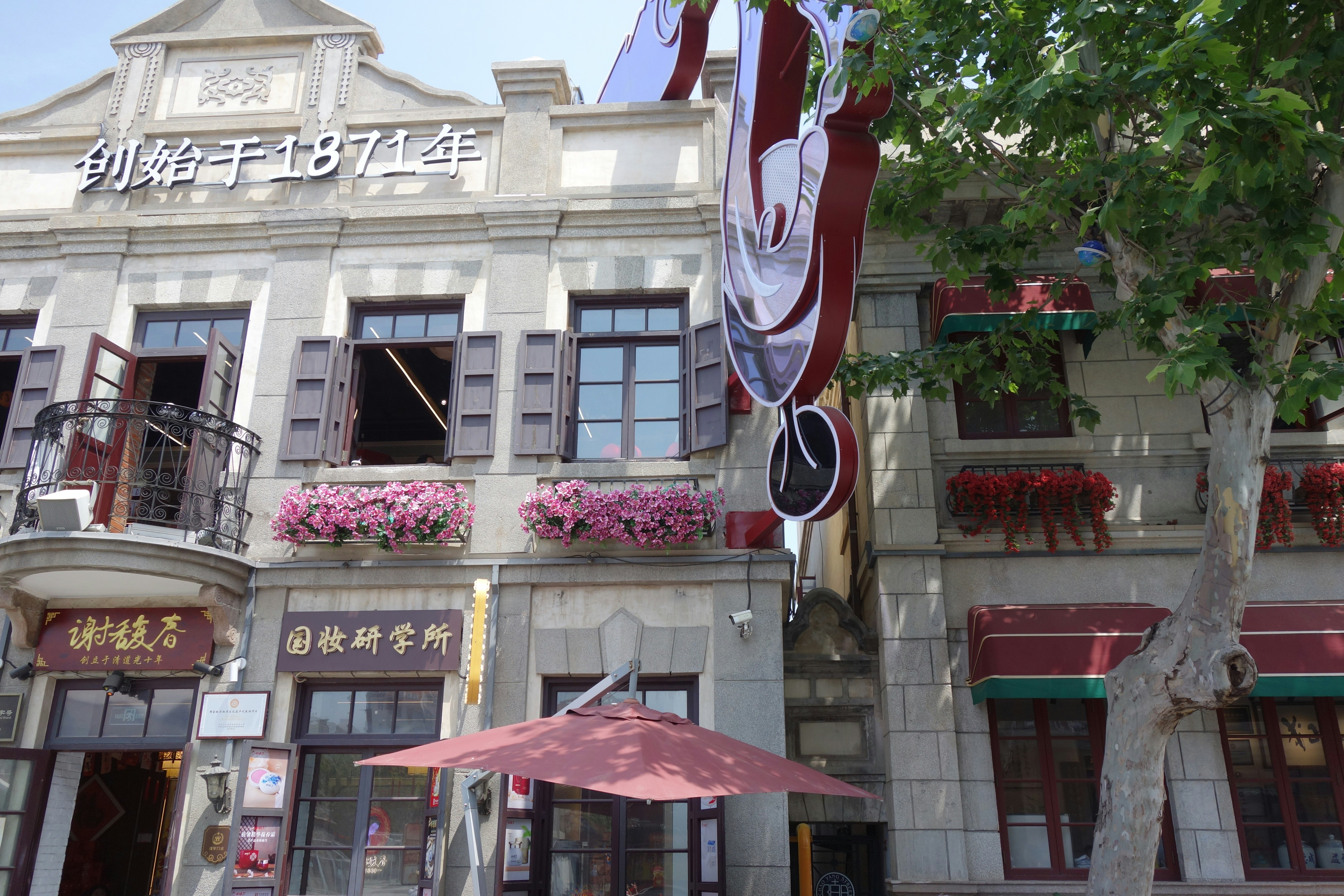 European-styled storefronts under a bright sky with a playful hanging sign