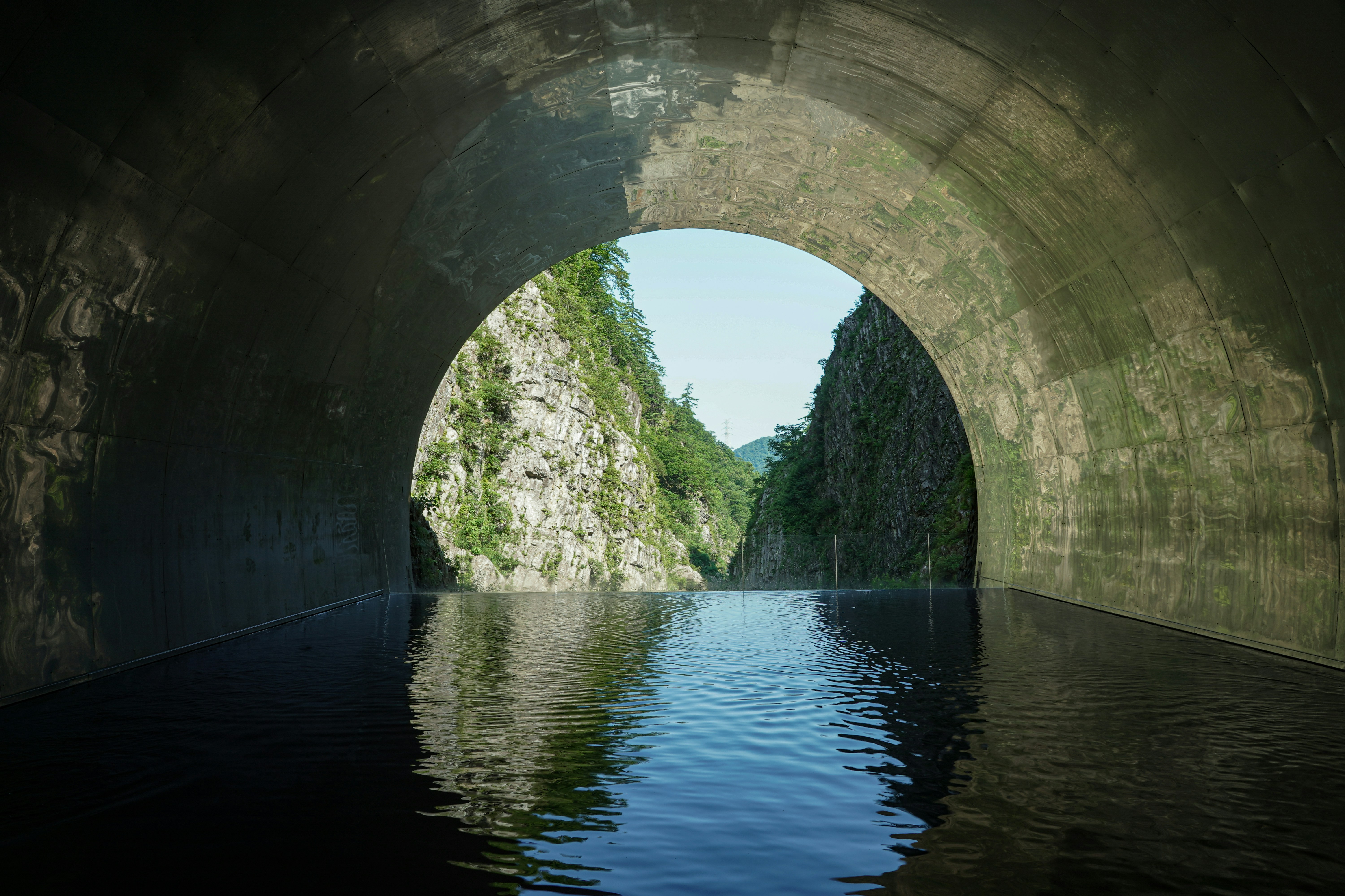 Light at the End: Ringed Tunnel Opening Framed by Surging River