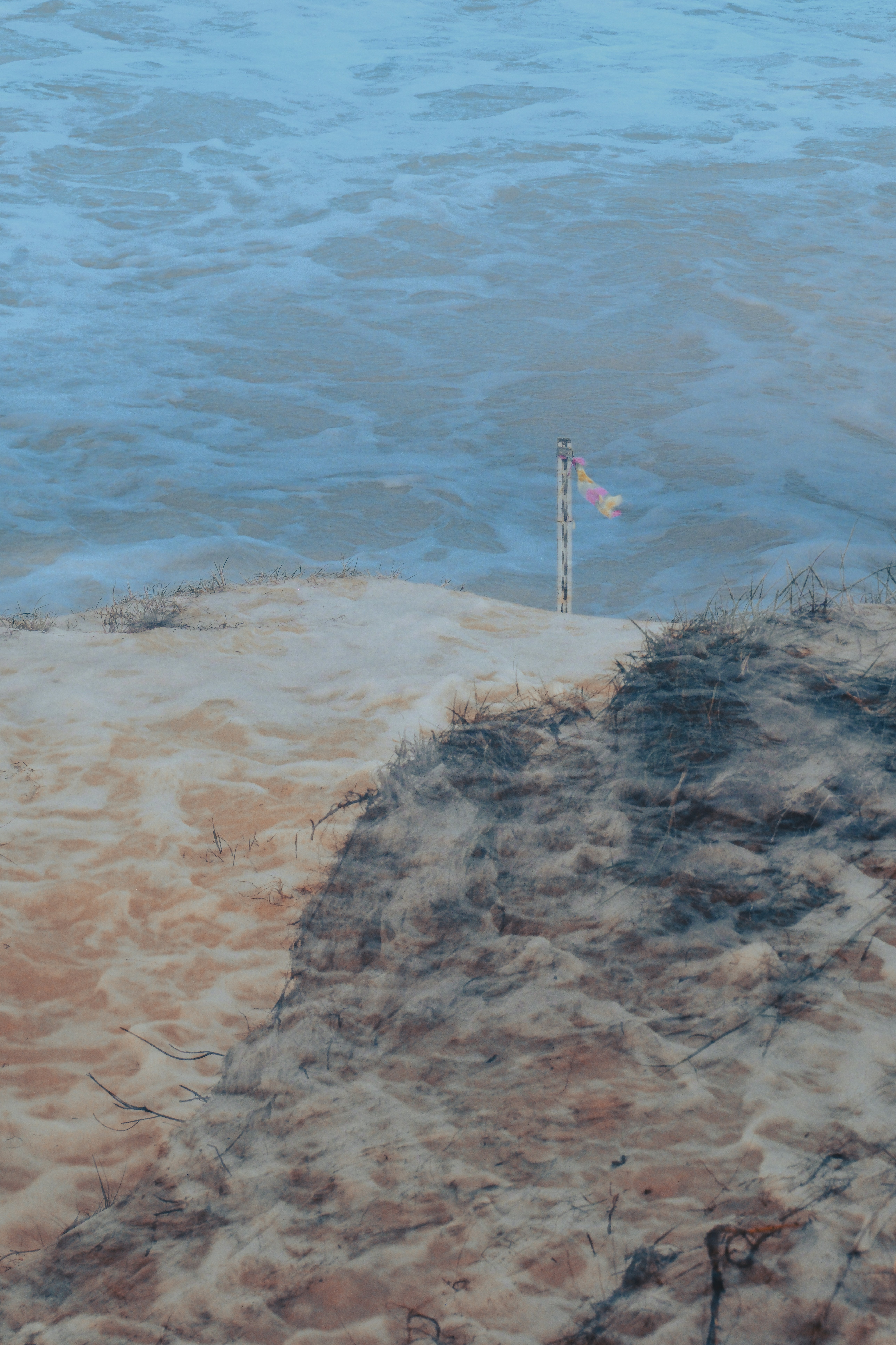 Marker Against the Dunes: A Lone Flag Bids Good Weather Farewell