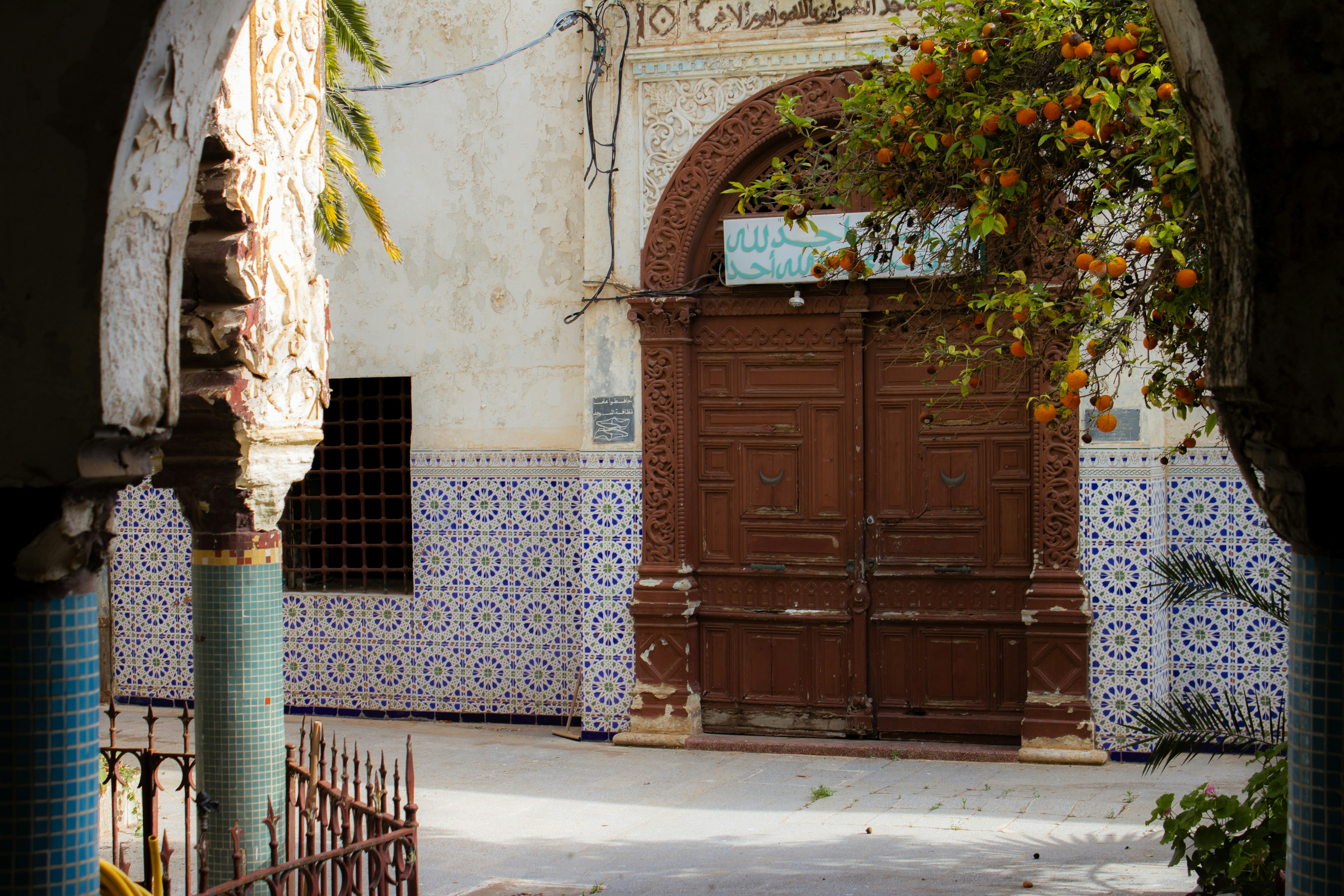 Blue-Tiled Courtyard Frame: A Weathered Doorway Beneath Blooming Arch