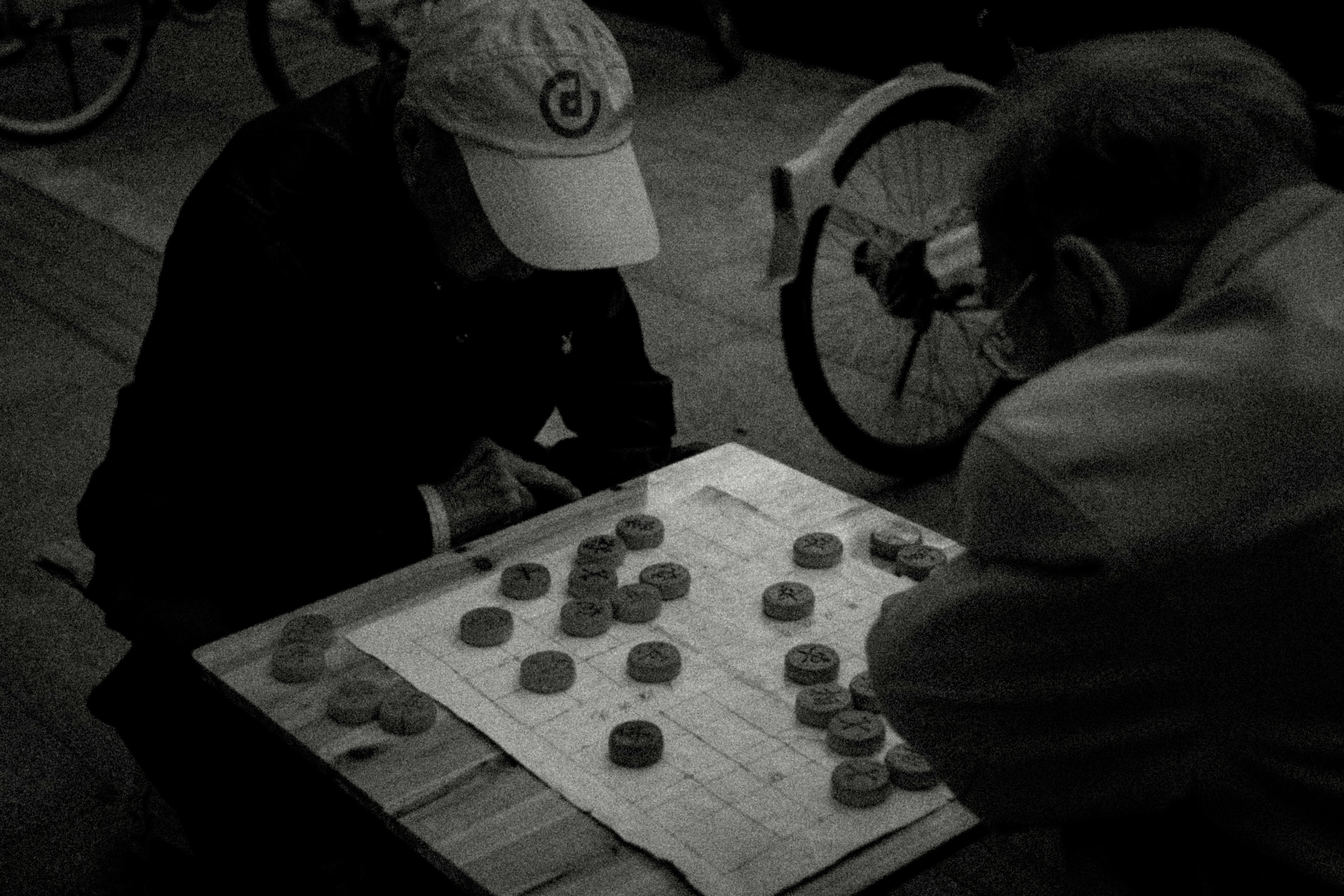 Midnight Match: Two Players Strategize Over a Board in Low Light