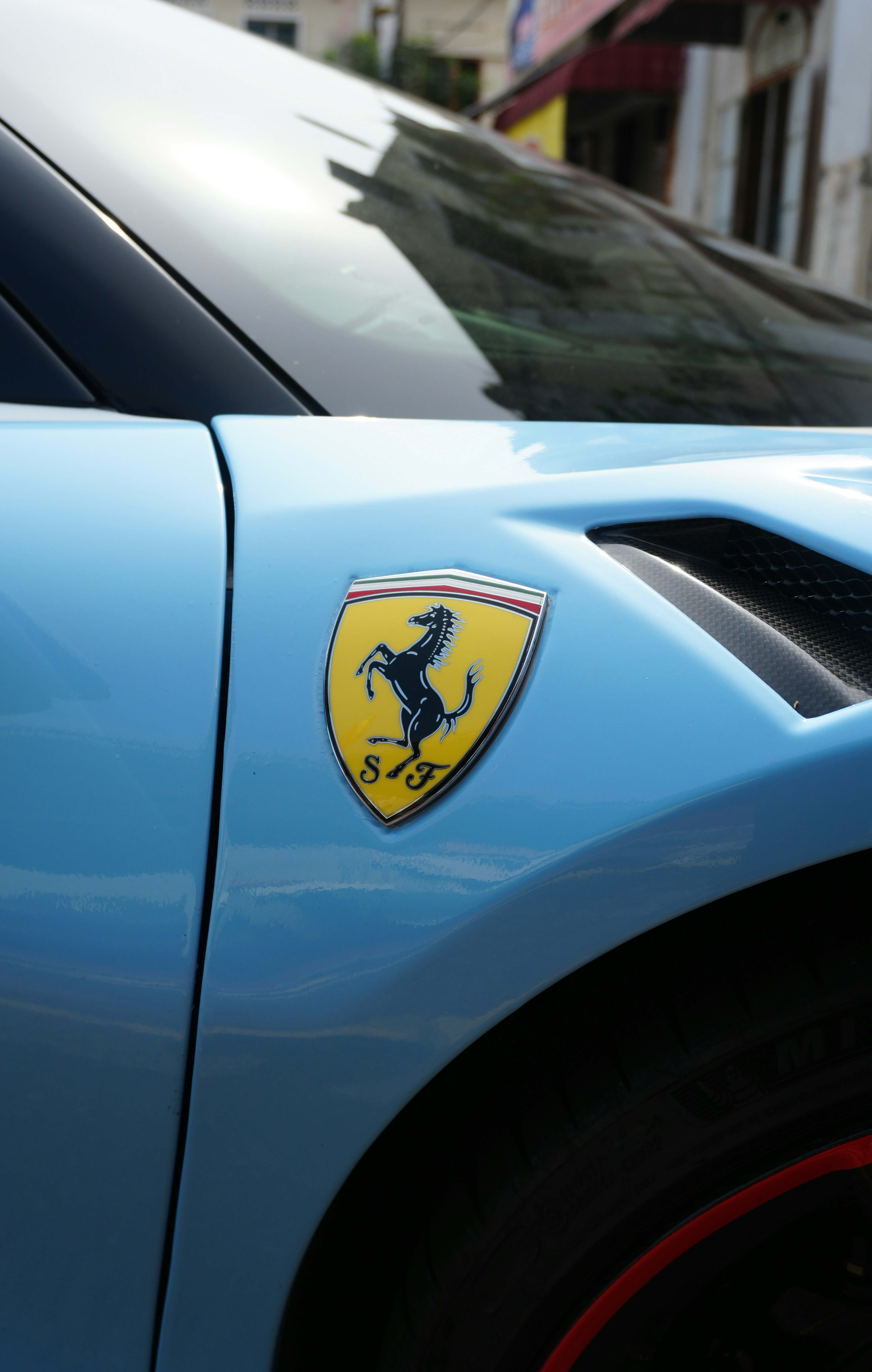 Close-up of a sky-blue Ferrari badge and front fender