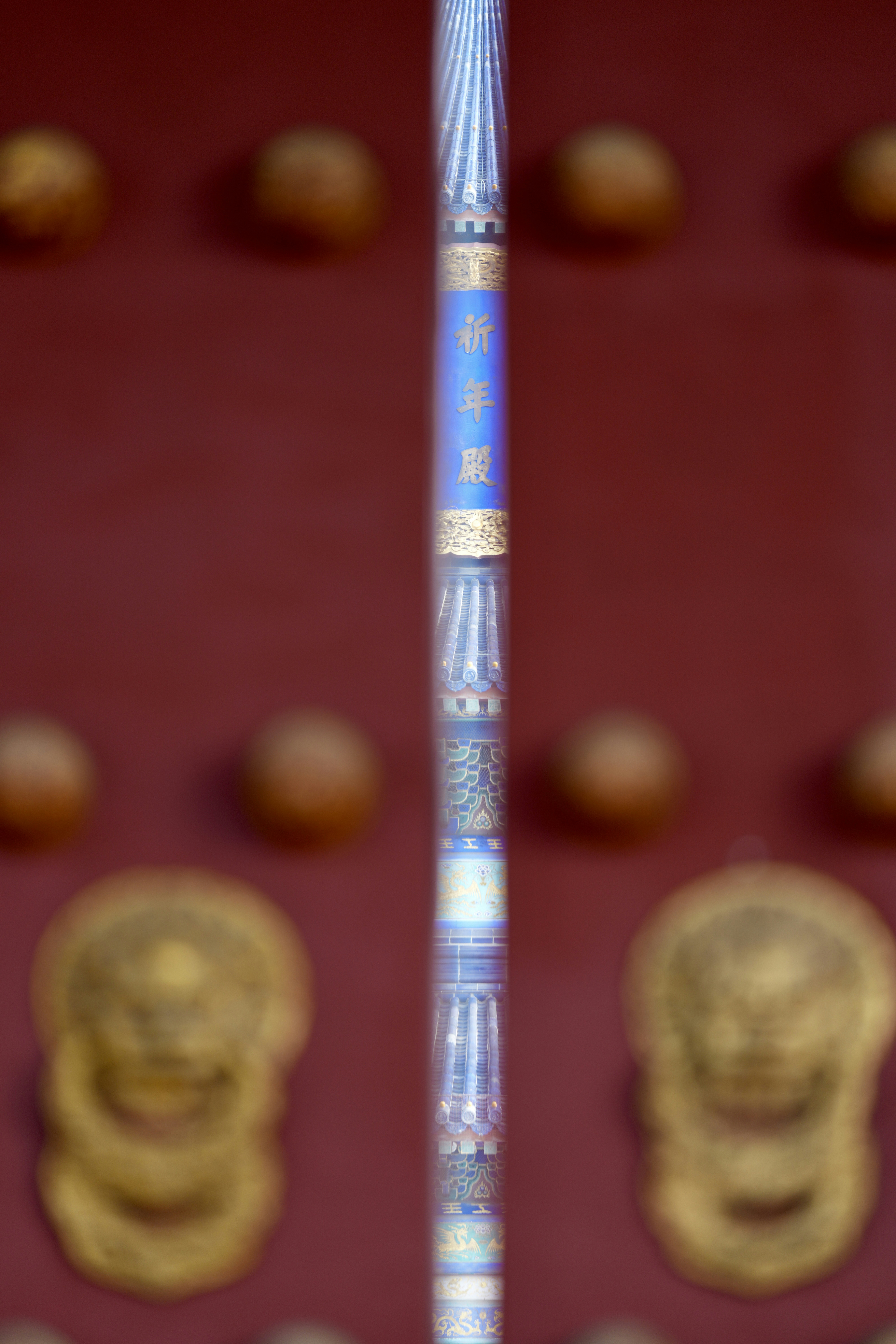 Vertical Ritual: a blue incense stick peeking through a red door